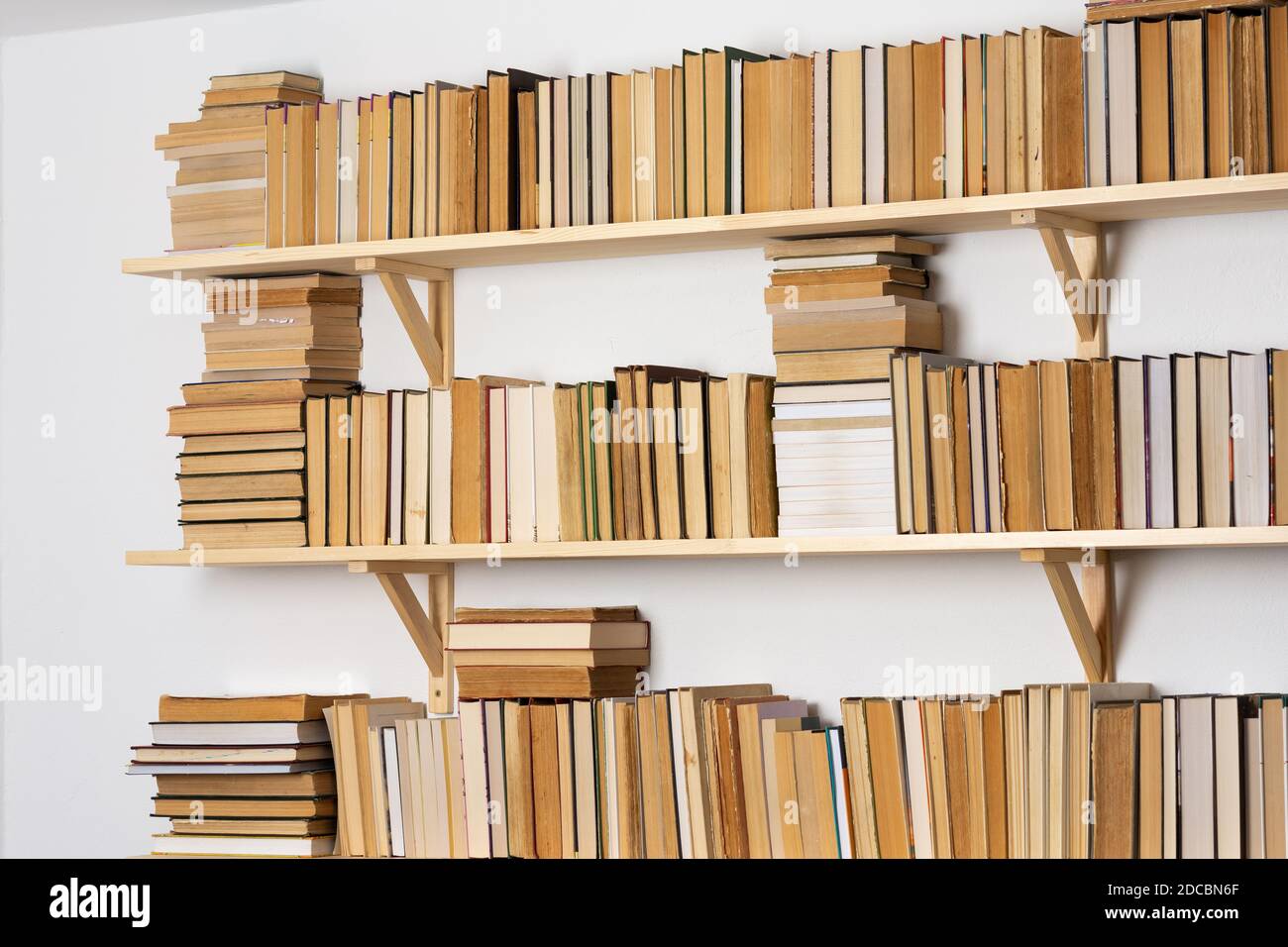 Light wooden bookshelves with hardback overturned books in white ...