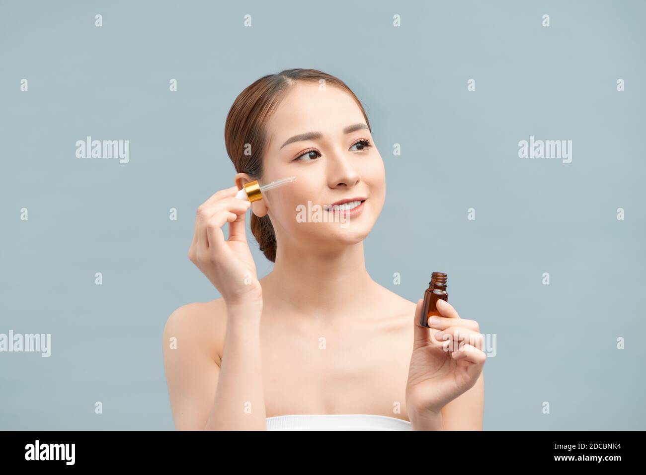 Beautiful model applying a cosmetic skin serum treatment on violet ...