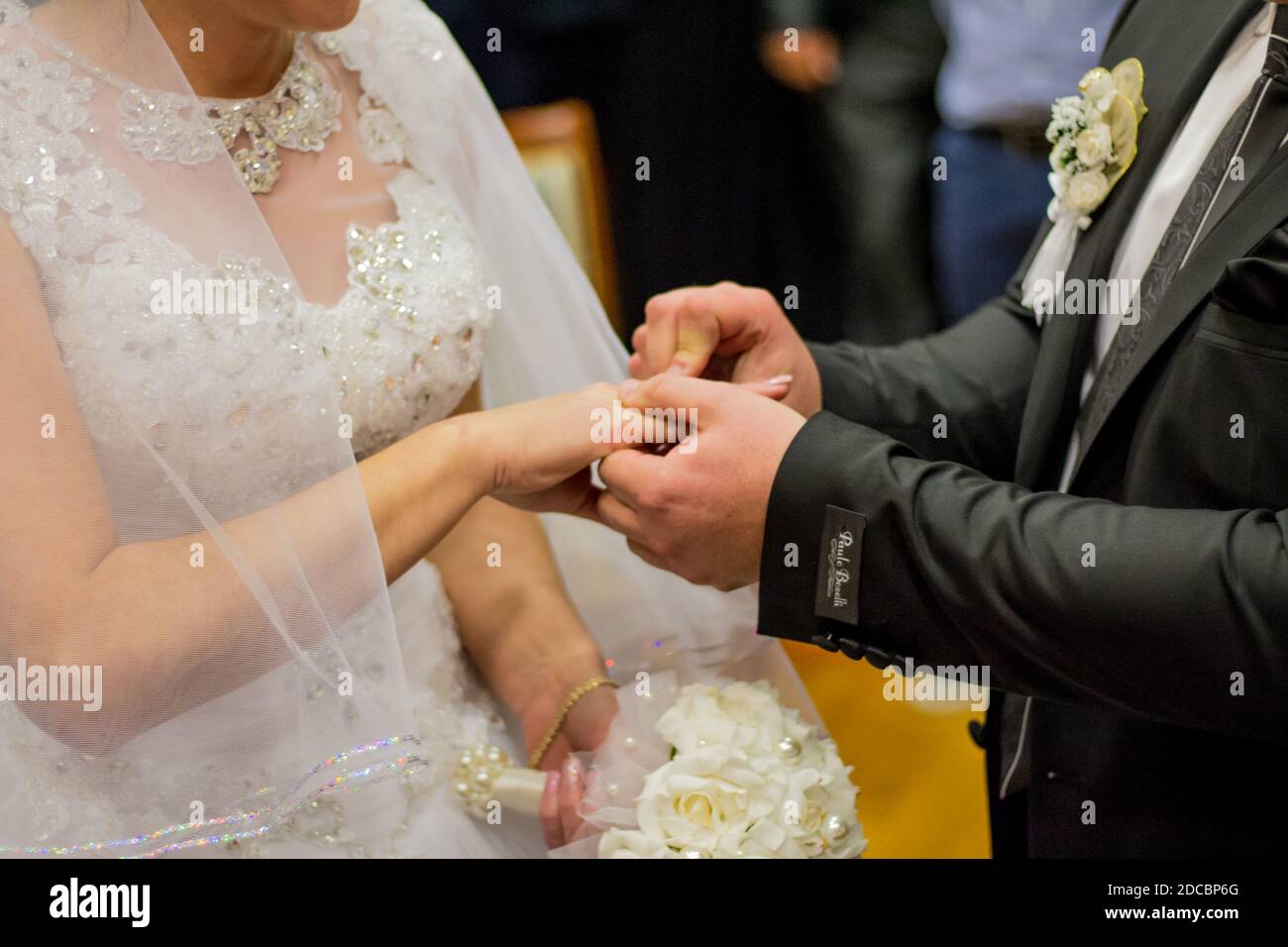 the groom putting the ring on the bride's finger Stock Photo - Alamy