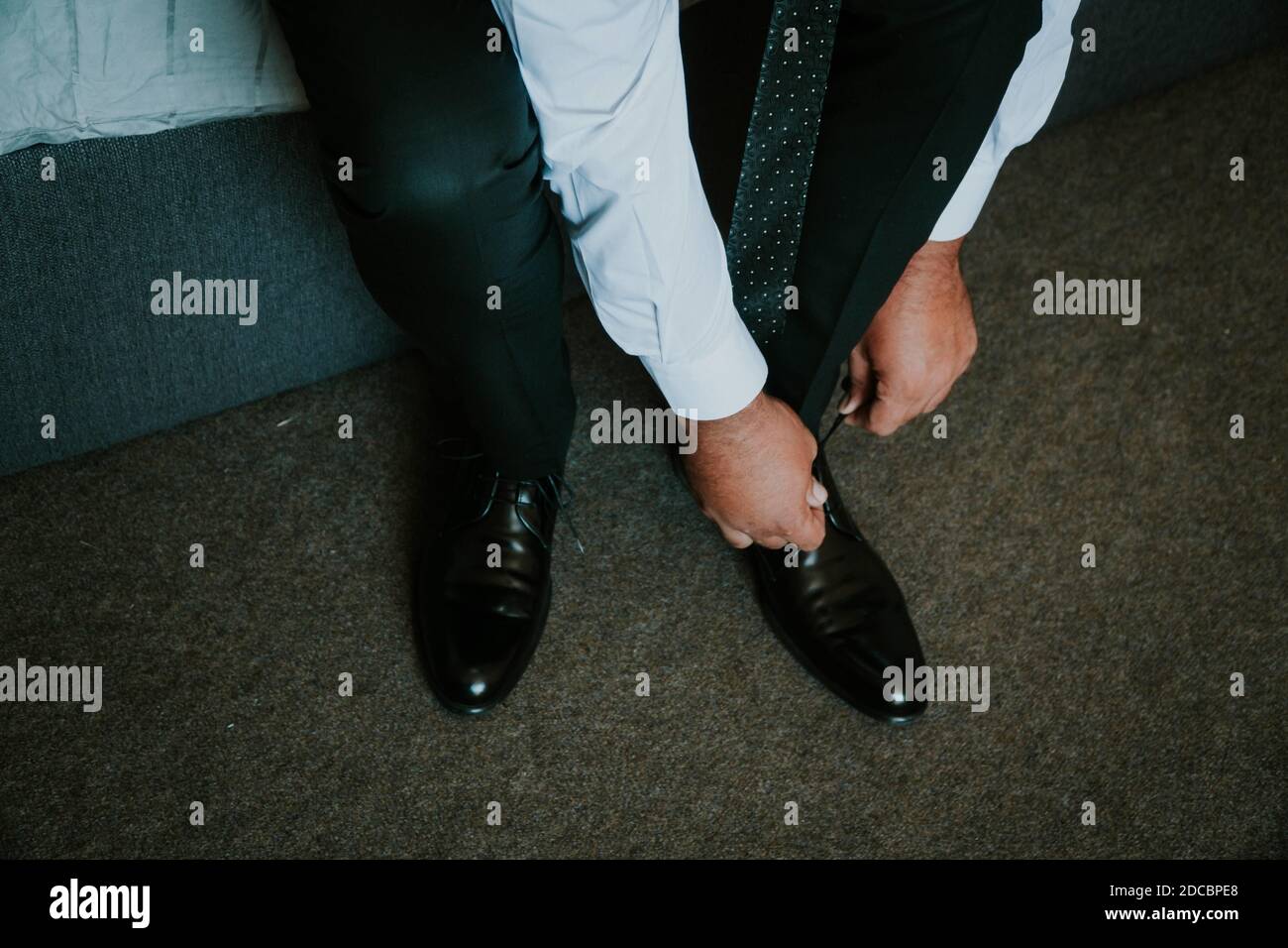 A closeup shot of a groom tying his shoes on the wedding day Stock ...