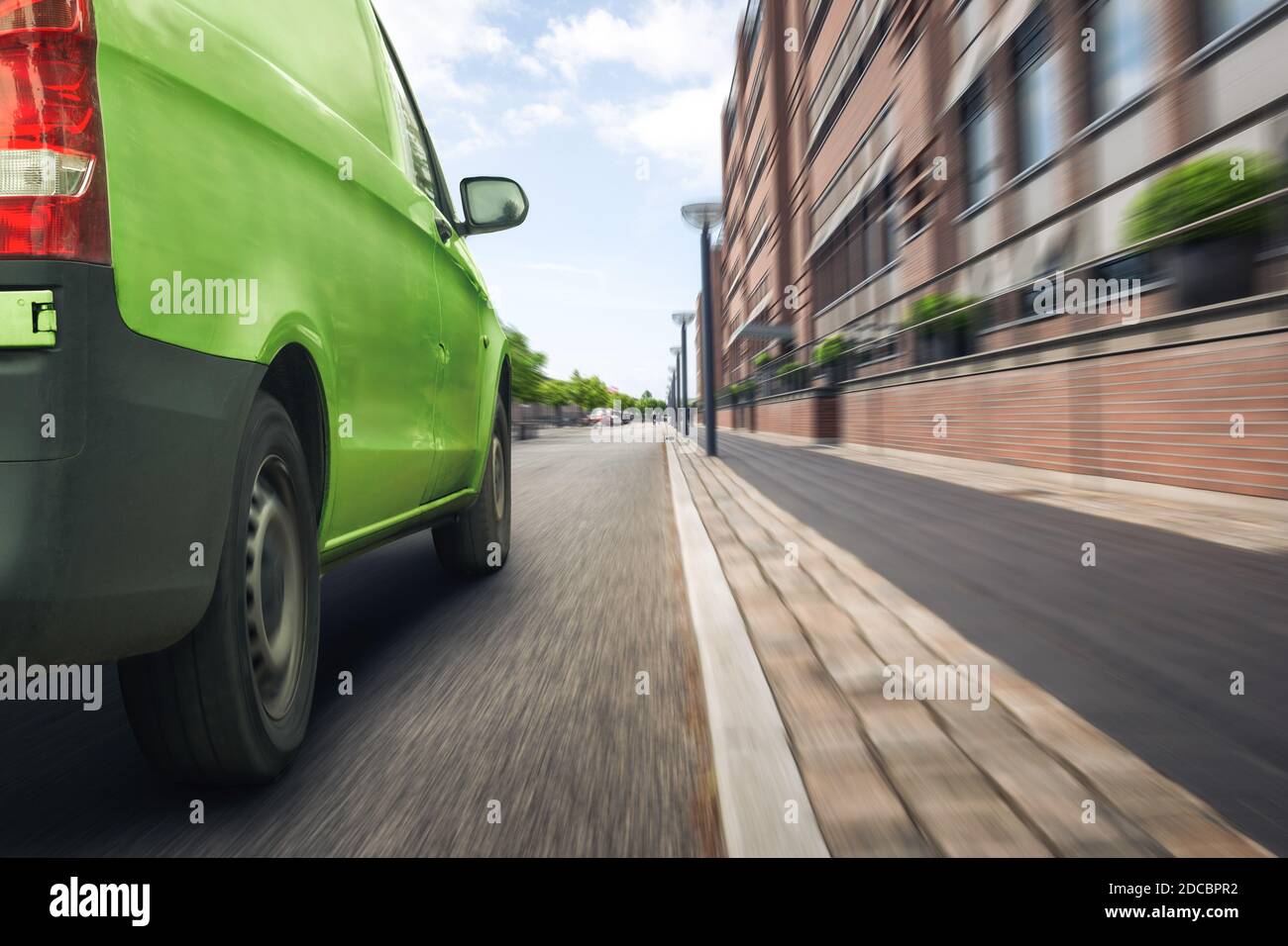 Green delivery van driving on a street in the city Stock Photo - Alamy