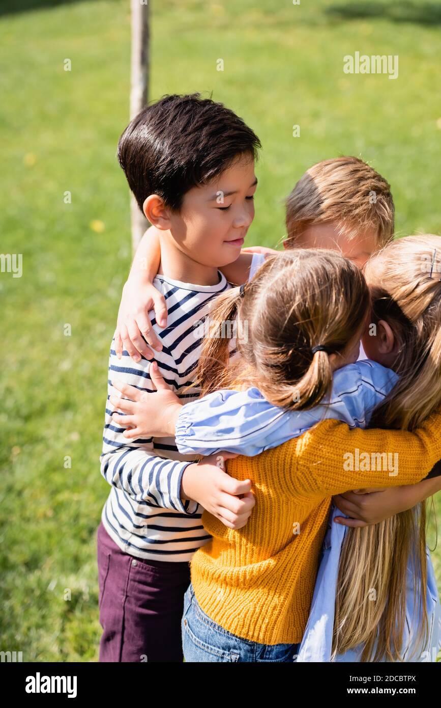 Asian boy hugging friends on blurred foreground in park Stock Photo - Alamy