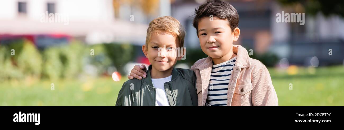 Asian boy hugging friend while looking at camera in park, banner Stock ...