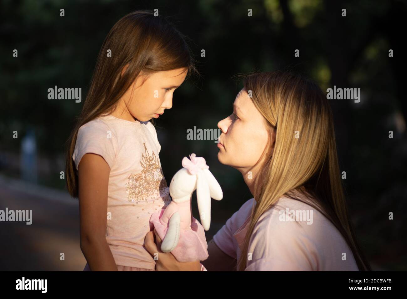 Young mother hugging her crying little daughter. Sad daughter in her ...