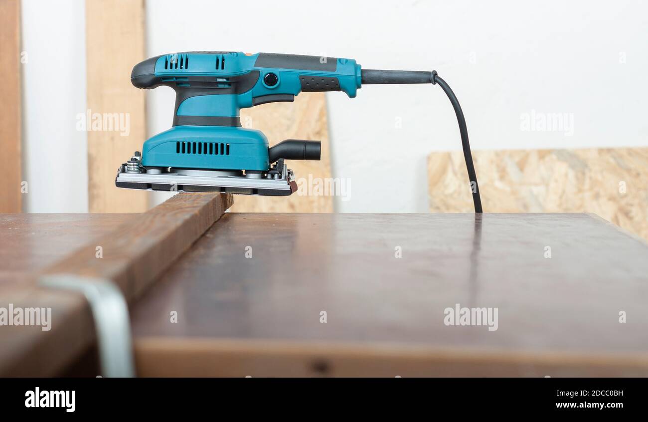 Electric sheet finishing sander on wood lath on desk, on background ...