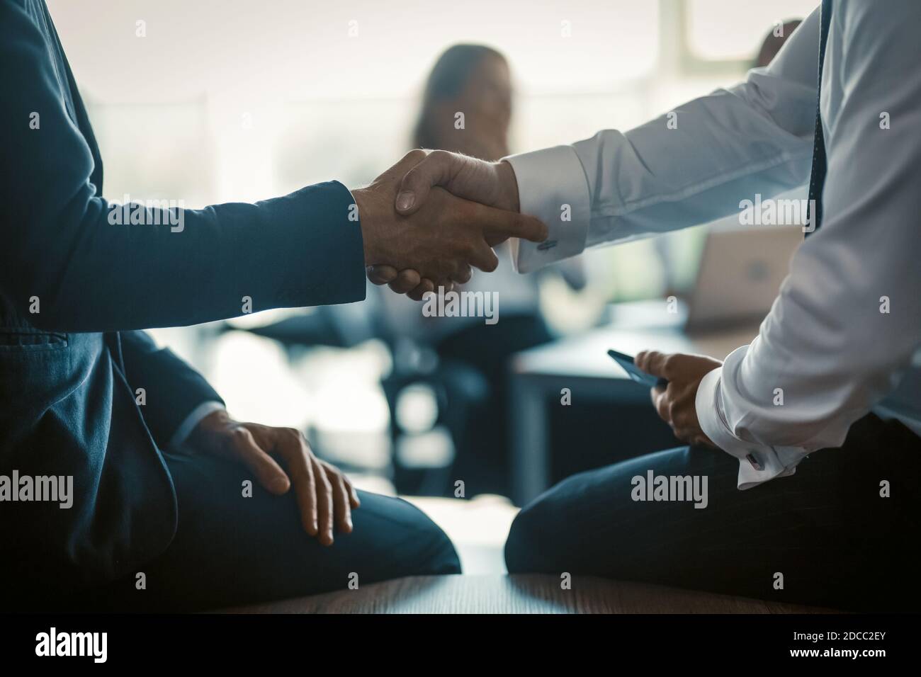 Handshaking of two business colleagues on modern office background ...