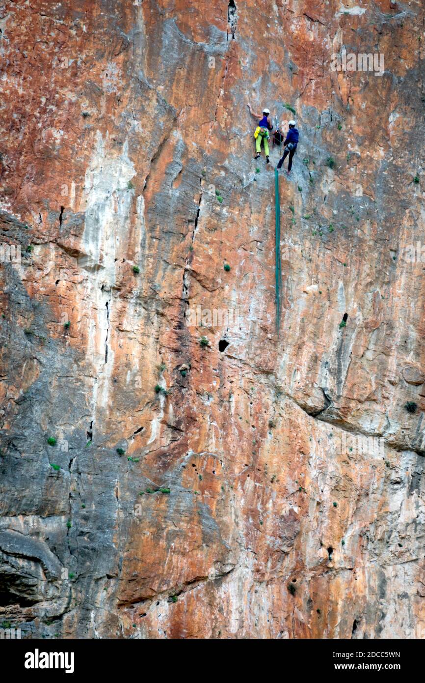 Two athletes practicing climbing on a vertical wall and high above the ...