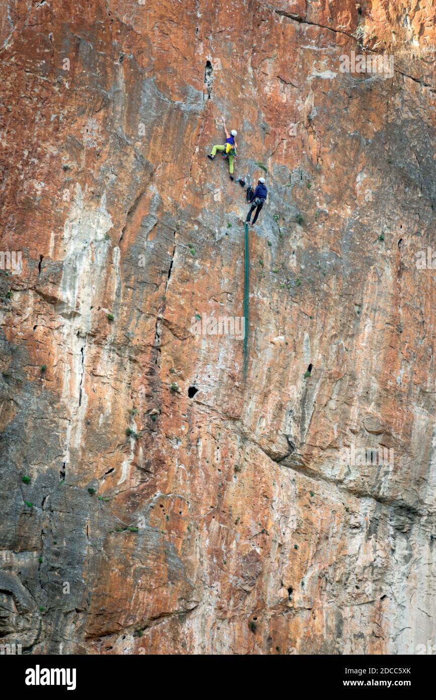 Two athletes practicing climbing on a vertical wall and high above the ...