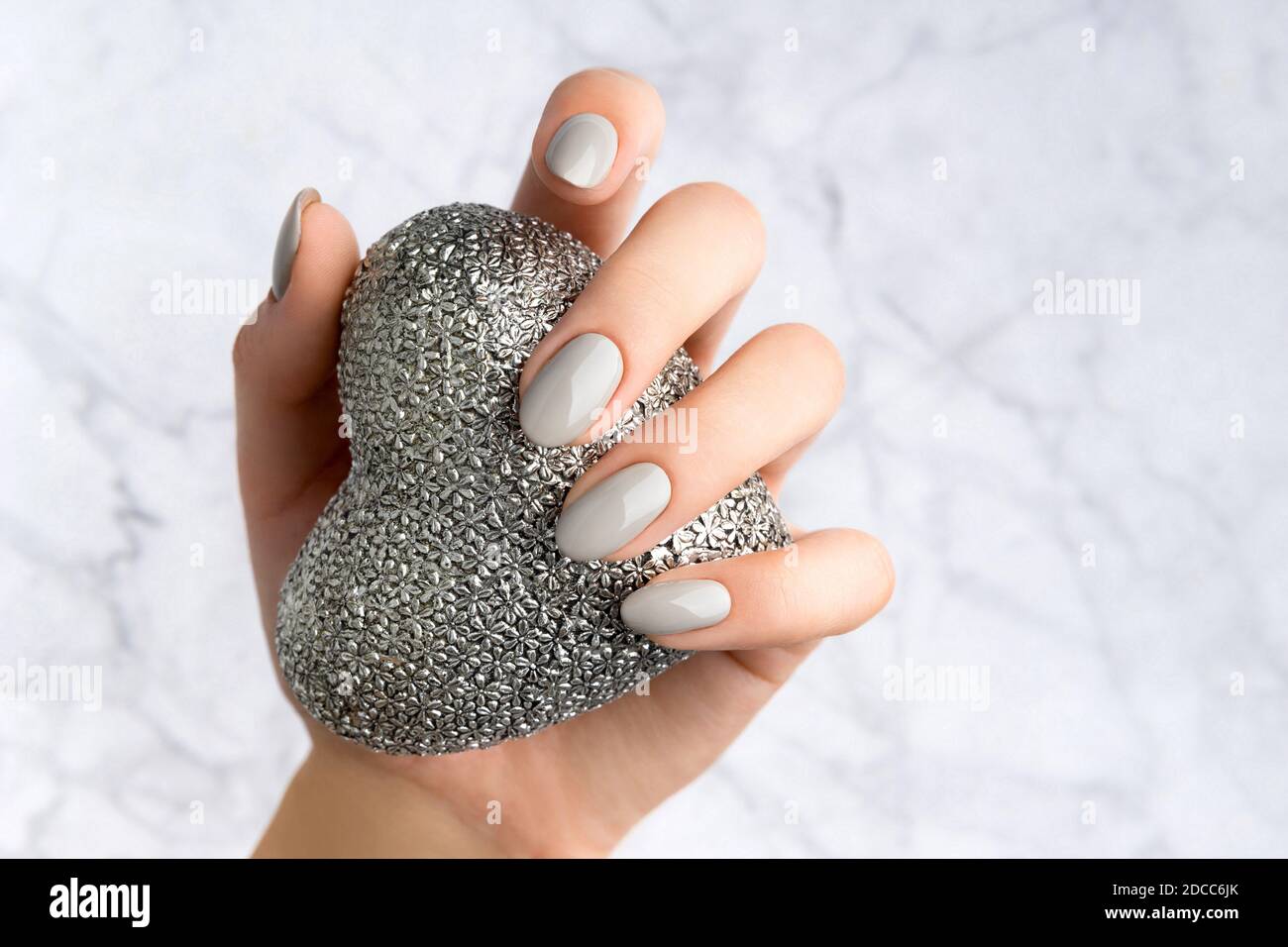 Beautiful womans hand with manicure holding silver heart Stock Photo ...