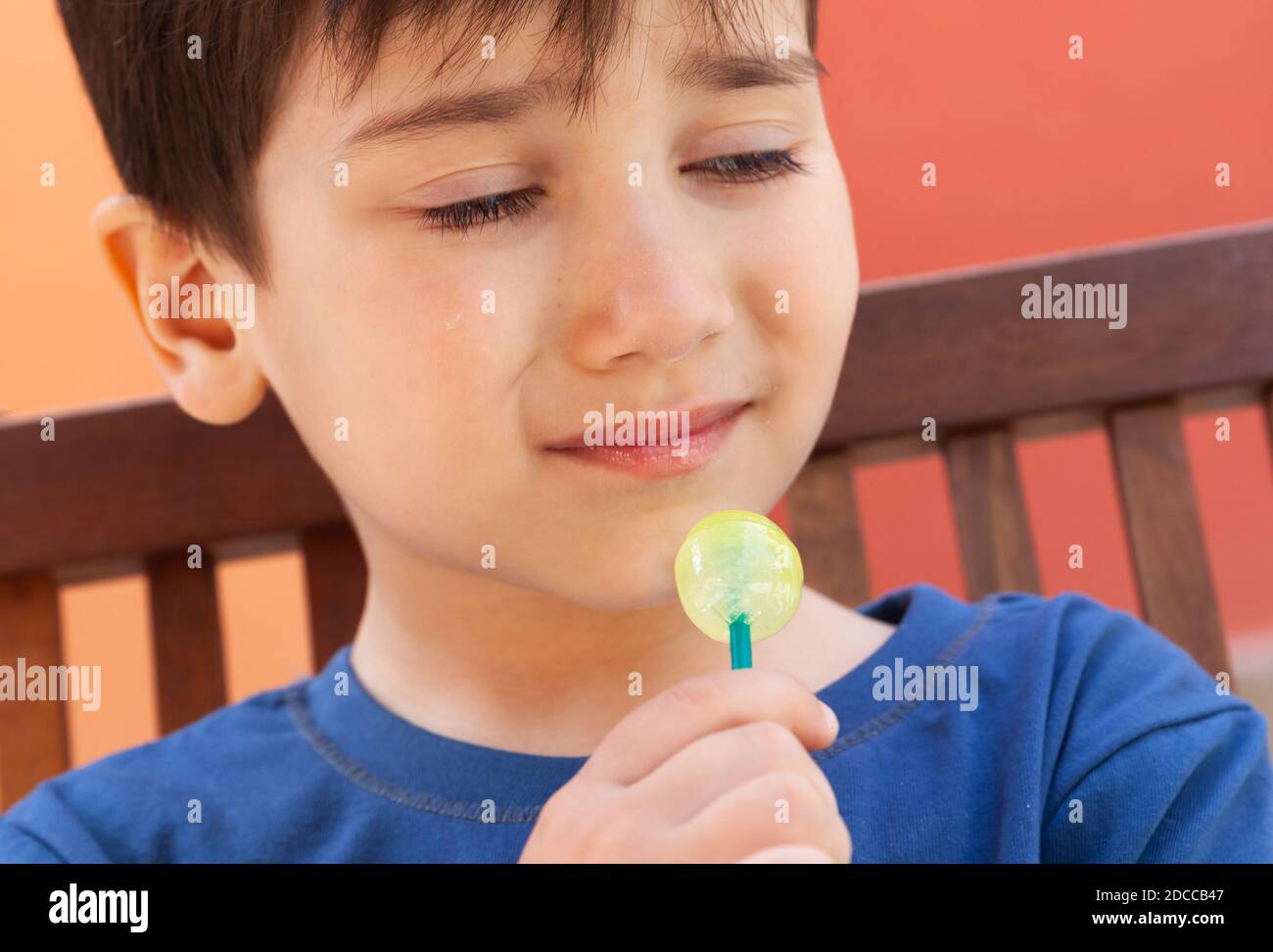Happy childhood concept. Cut little boy eating lollipop candy and ...