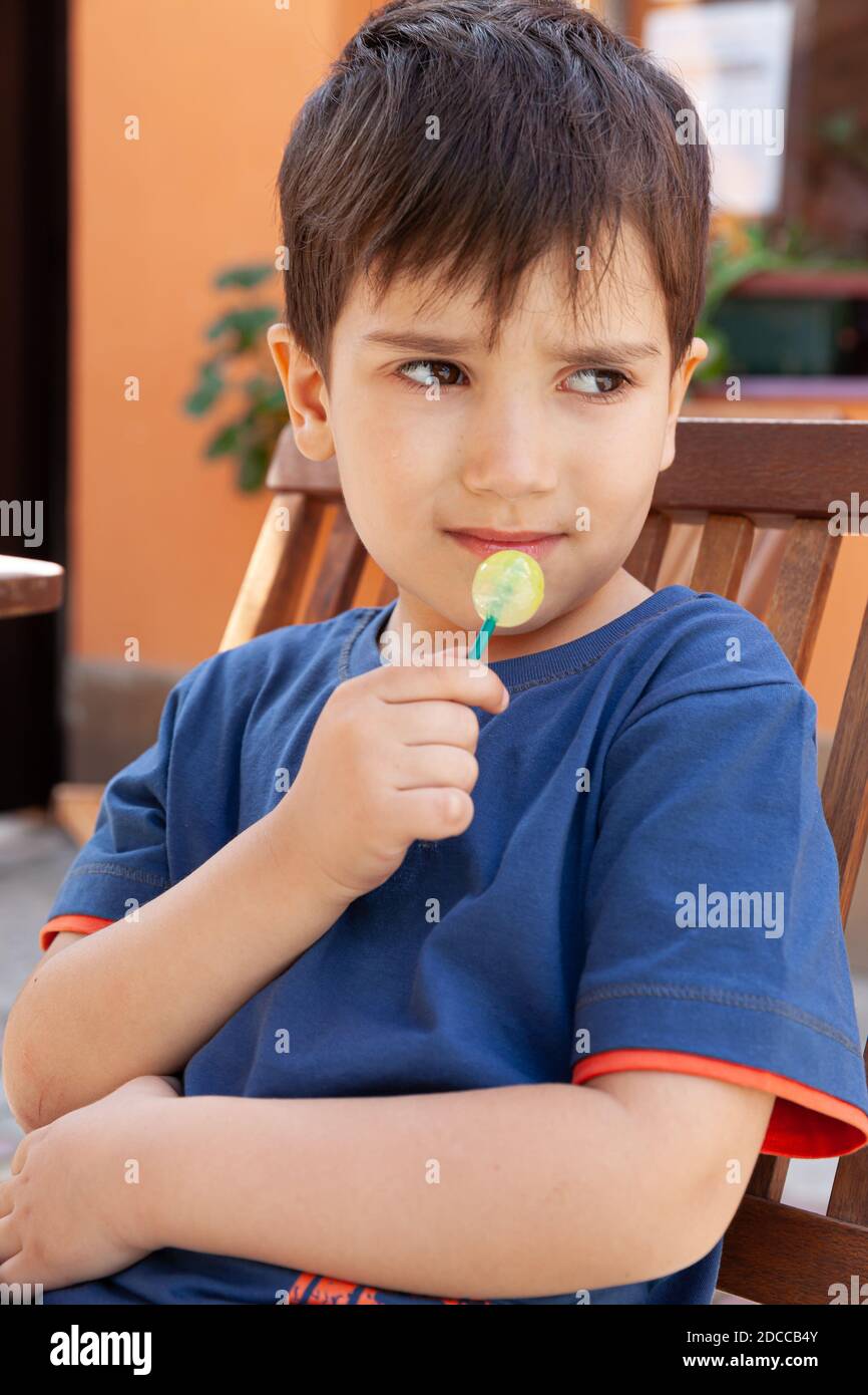 Happy childhood concept. Cut little boy eating lollipop candy and ...