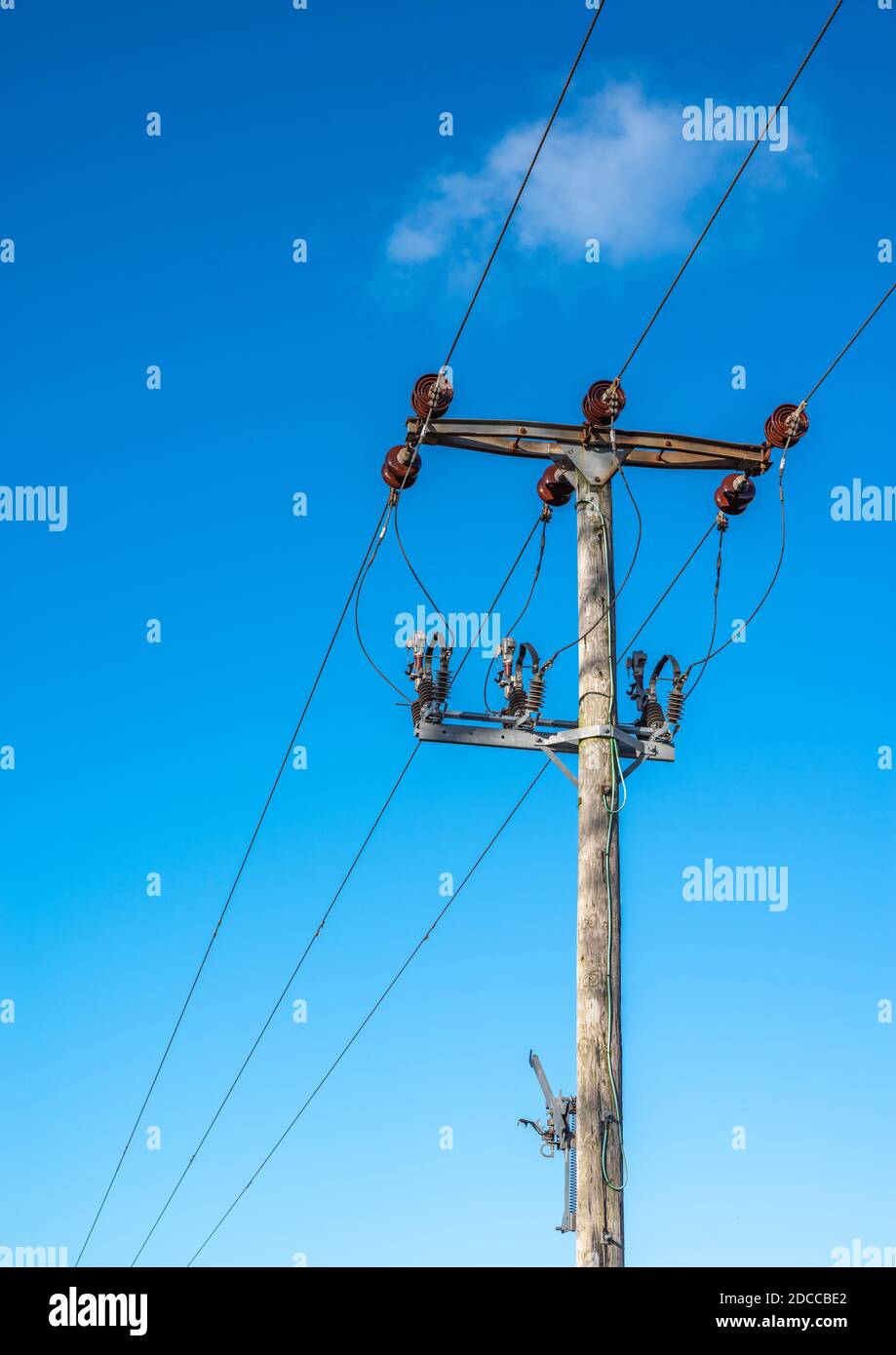Wooden telegraph pole with wires and insulators with a clear blue sky ...