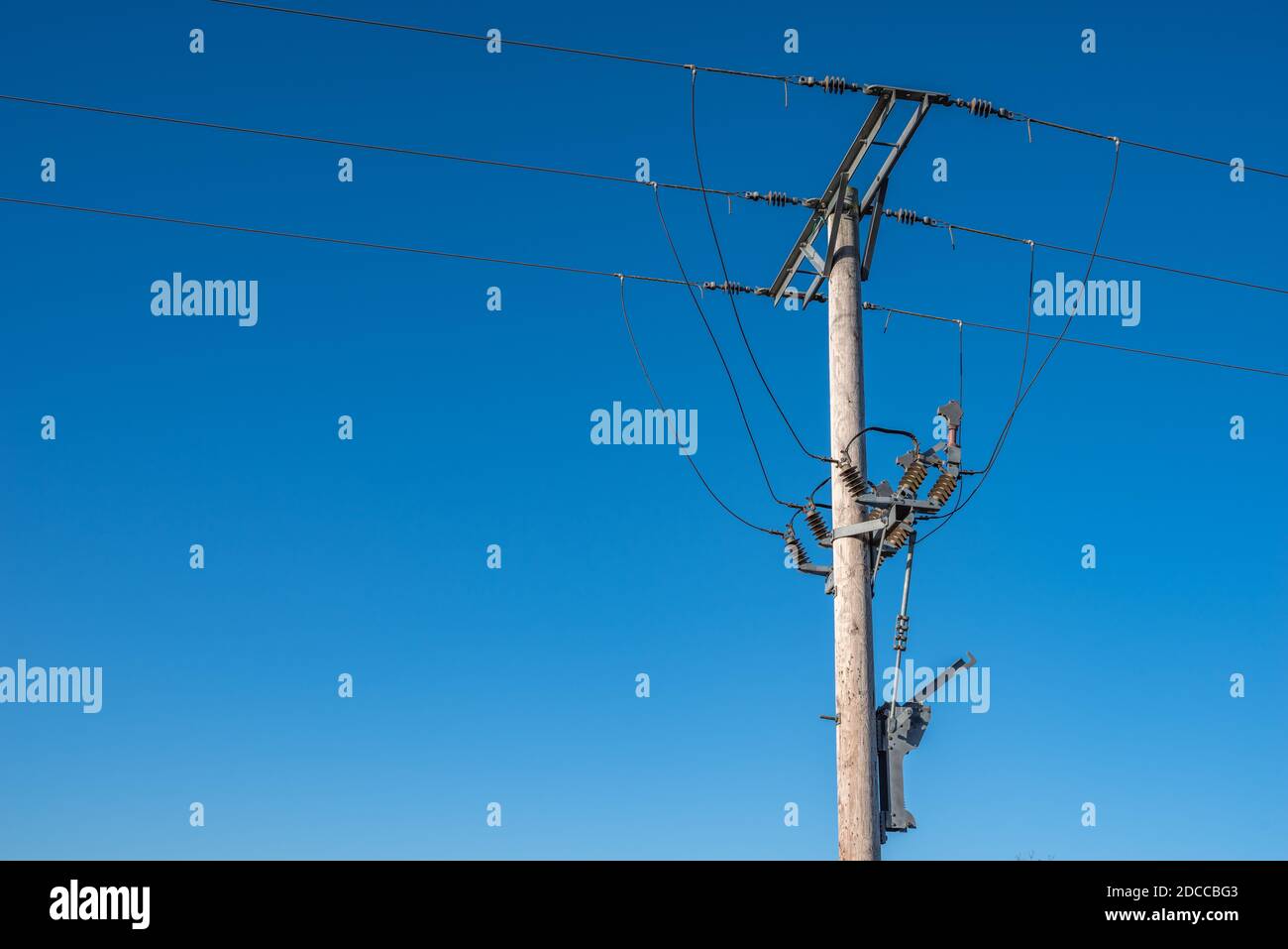Wooden telegraph pole with wires and insulators with a clear blue sky ...