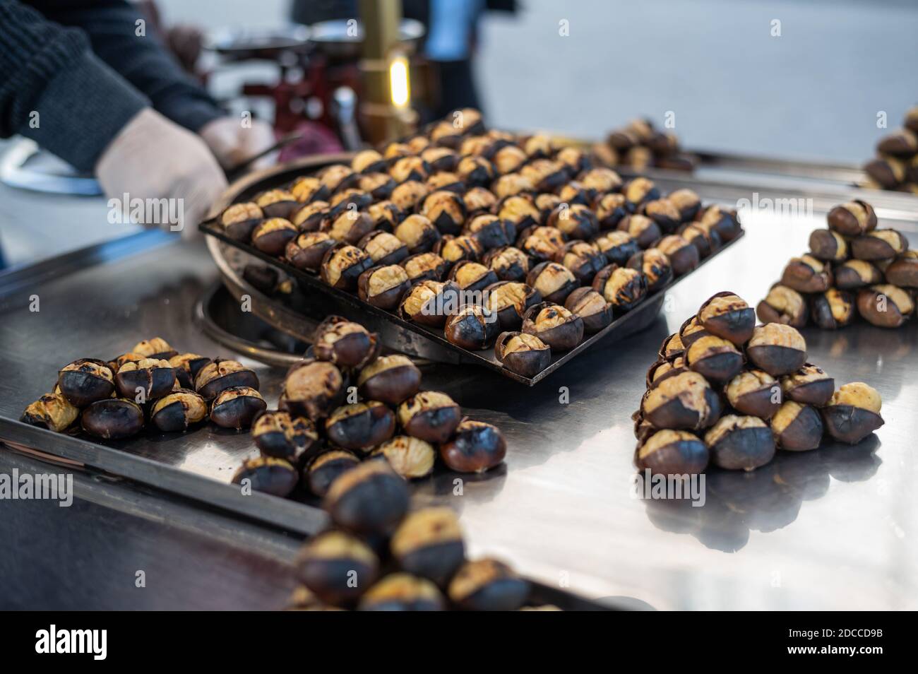Male salesman is cooking Roasted chestnuts on a city street. Street ...