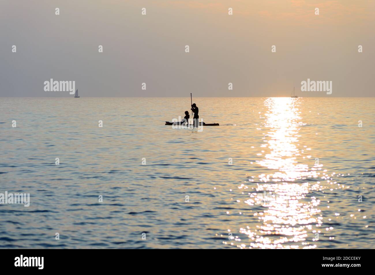 Young couple paddling in the ocean at sunset time Stock Photo - Alamy