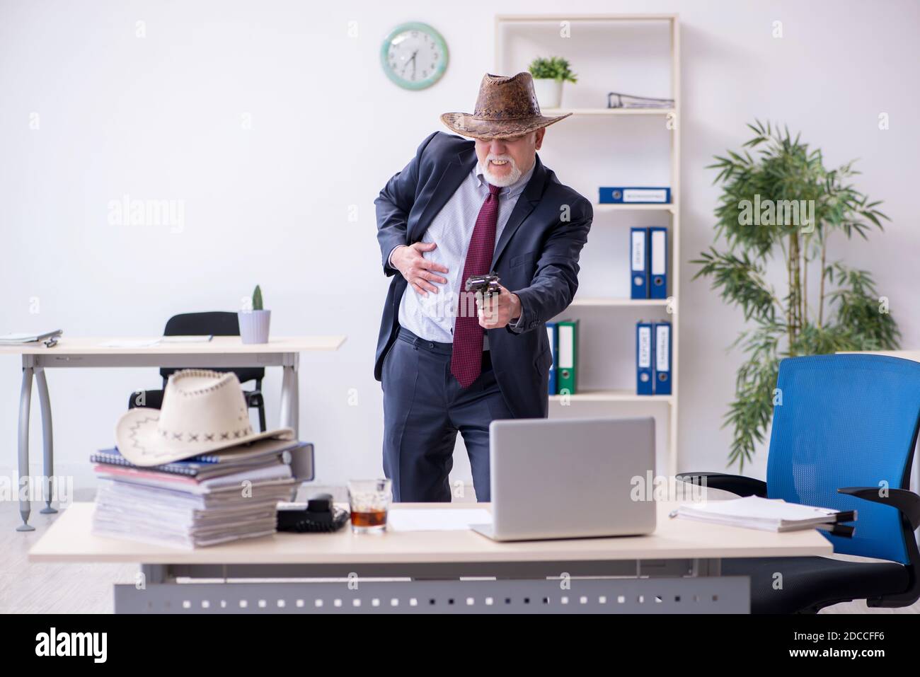 Funny old boss in cowboy hat in office Stock Photo - Alamy