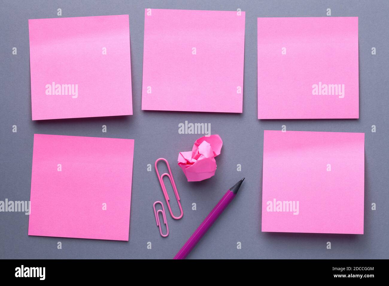 Pink sticky note paper with office supplies on grey paper background ...