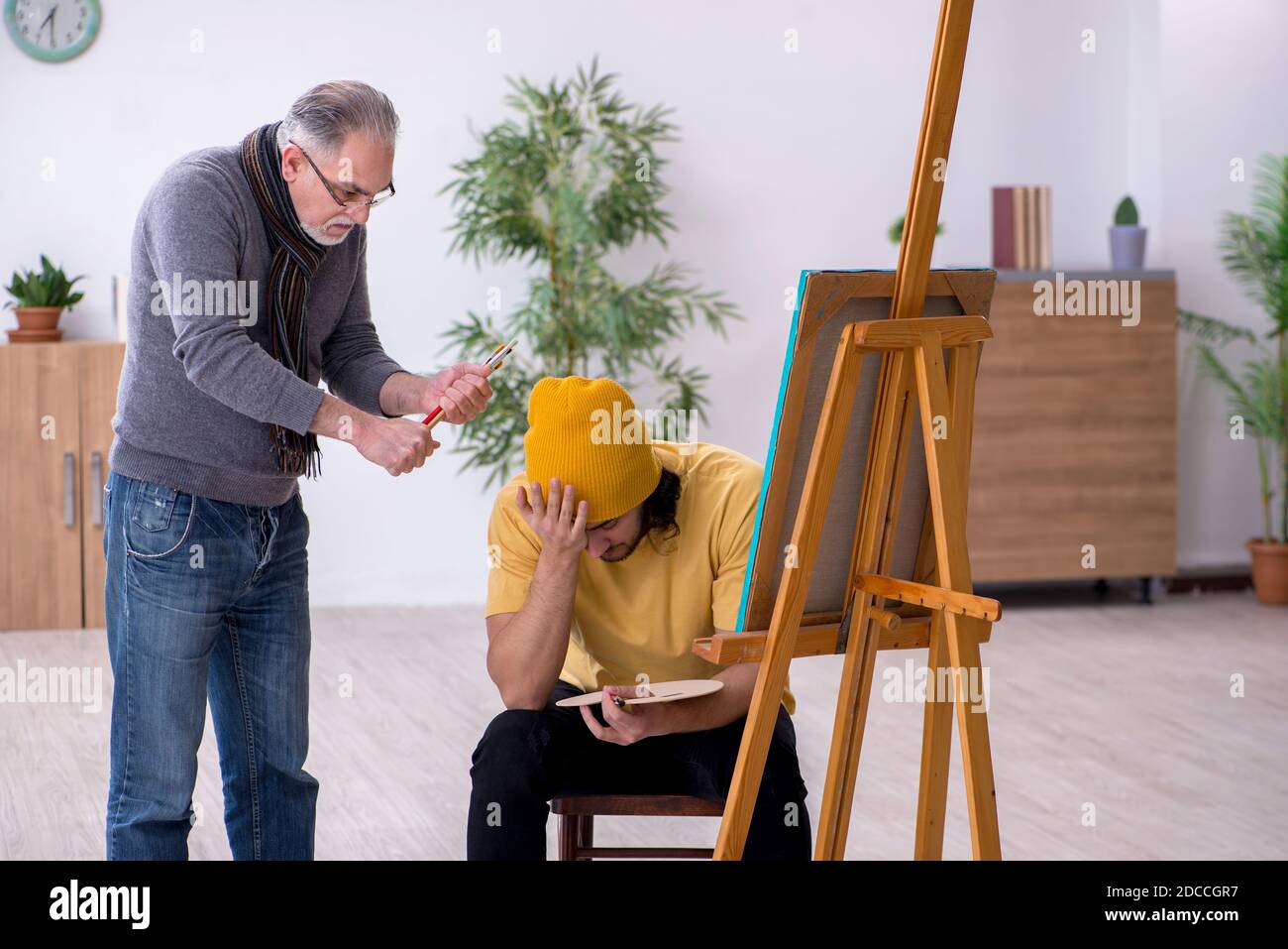 Young man taking lesson from experienced painter Stock Photo - Alamy