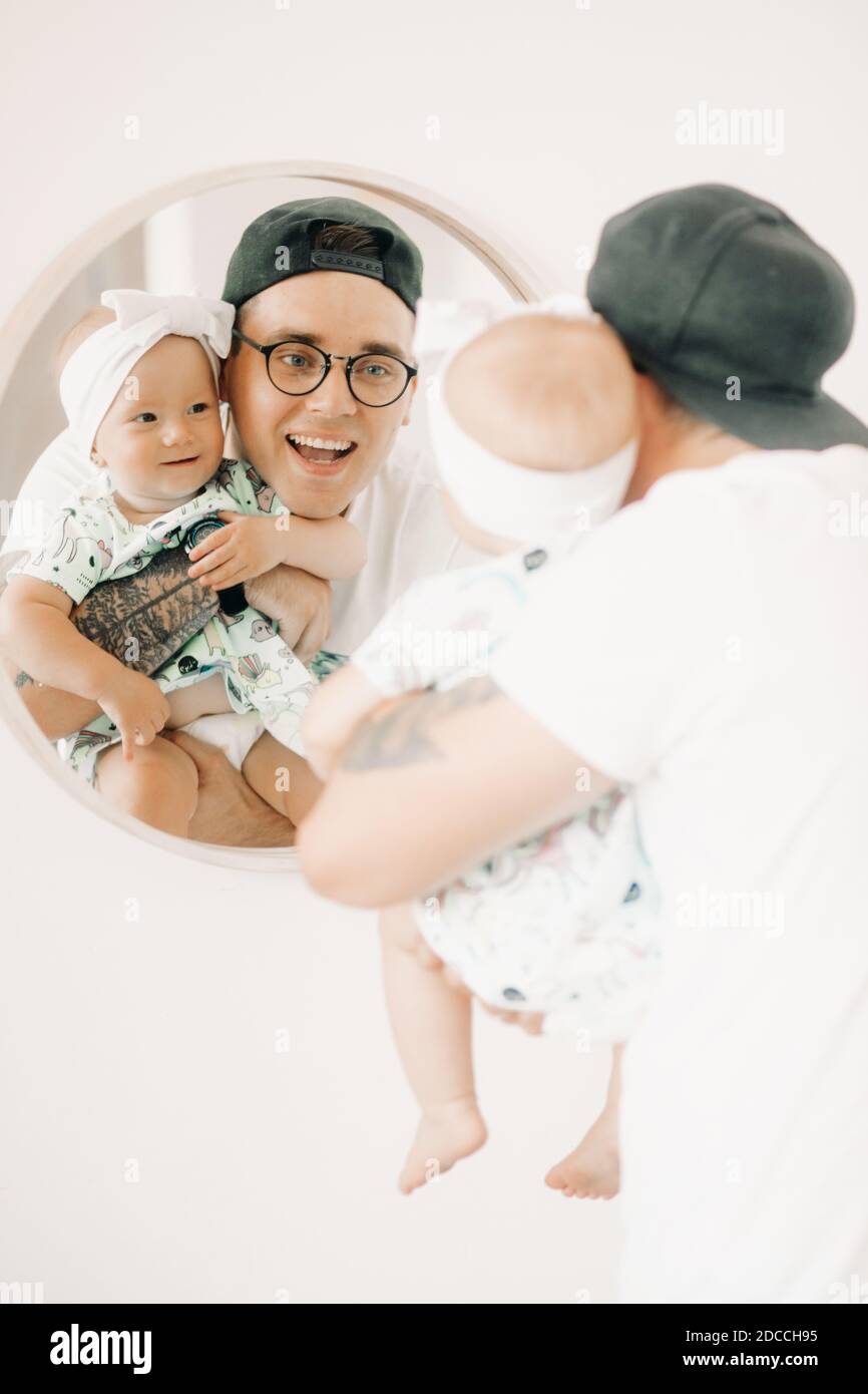 Father plays with his little daughter and looks at their reflection on ...