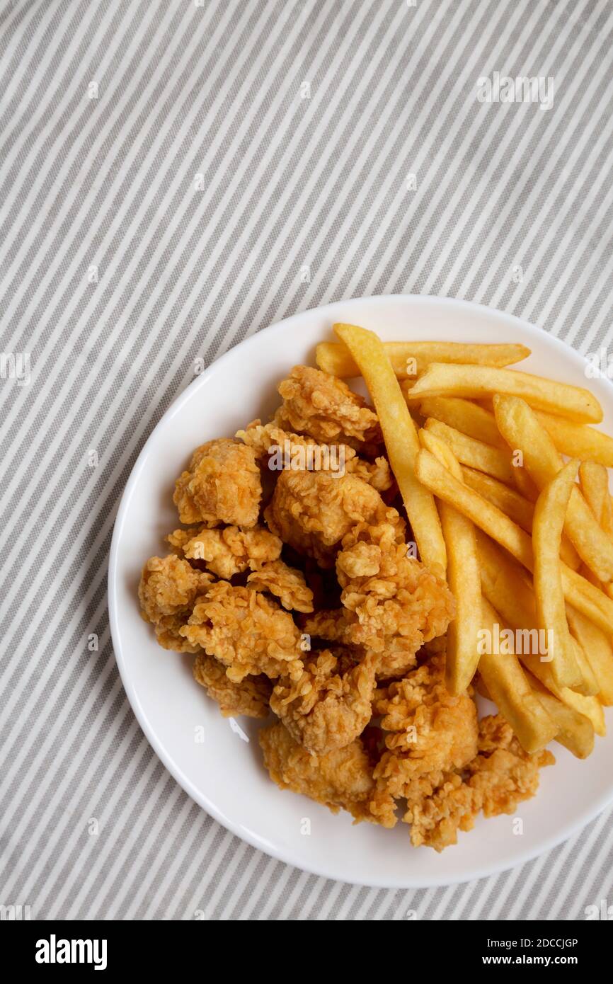 Homemade Fried Chicken Bites and French Fries on a plate on cloth ...