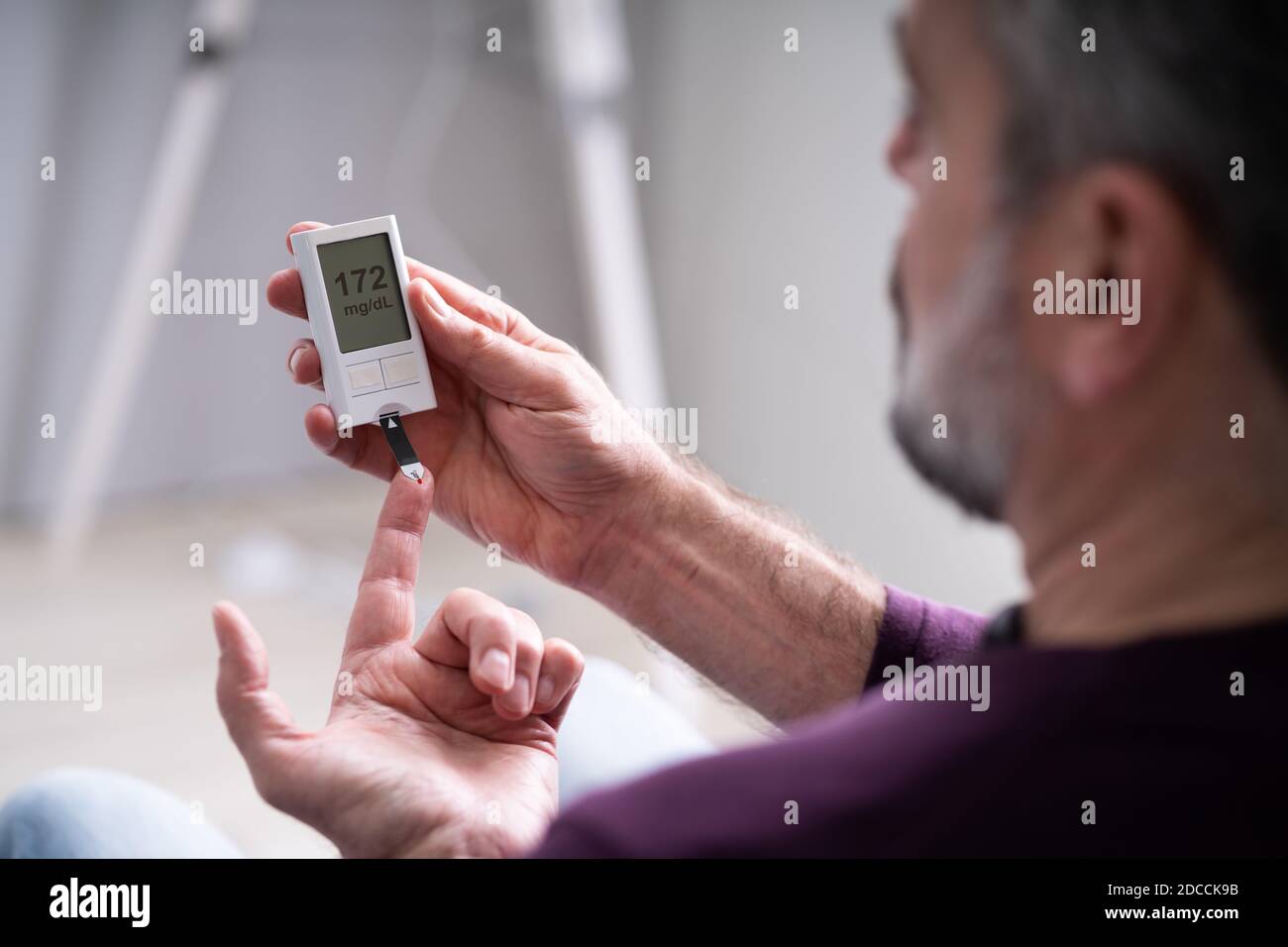 Elderly Man Using Glucometer To Check Blood Sugar Level At Home Stock ...