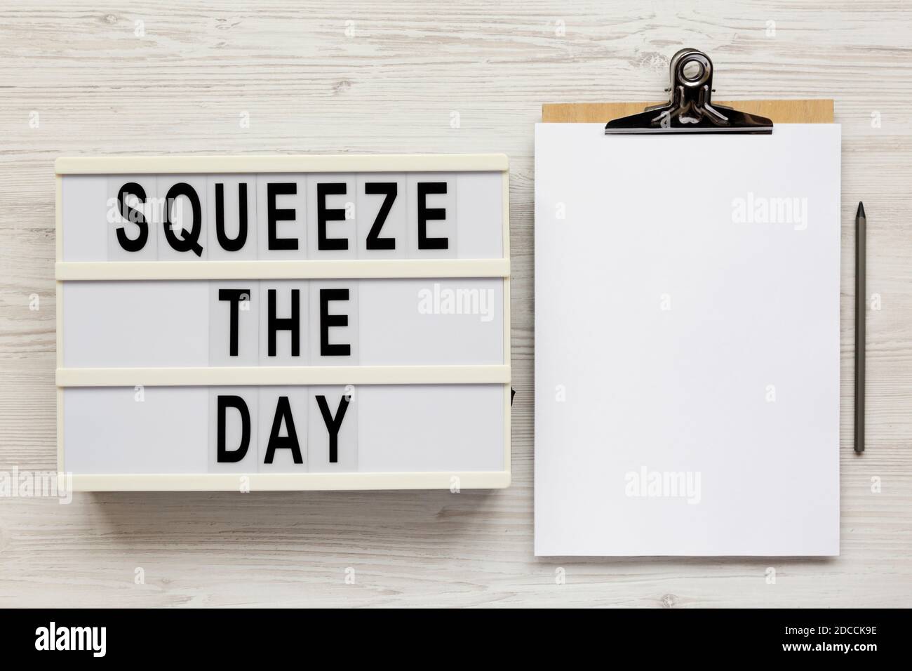 'Squeeze the day' on a lightbox, clipboard with blank sheet of paper on ...