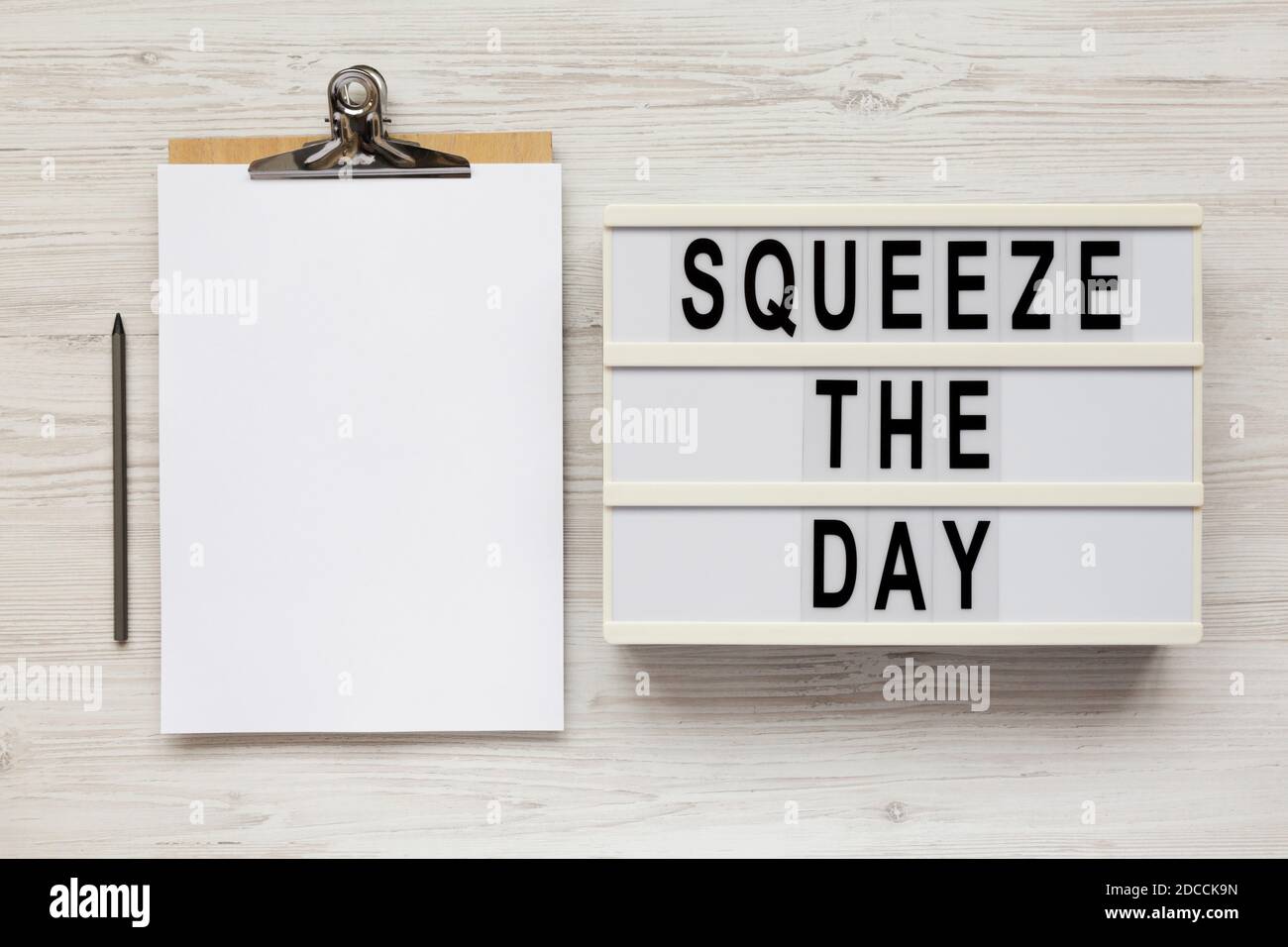 'Squeeze the day' on a lightbox, clipboard with blank sheet of paper on ...