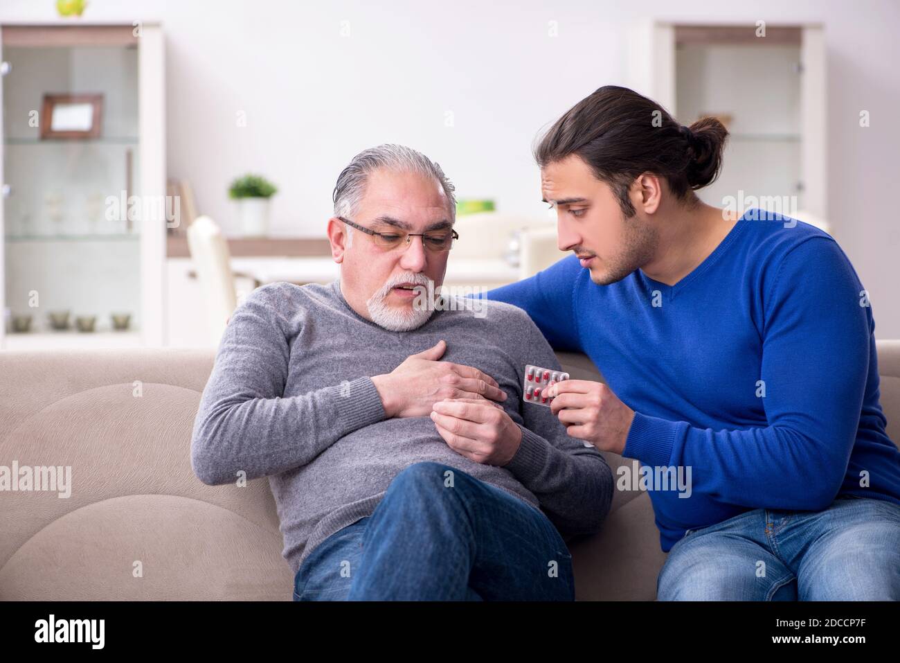 Young man looking after his sick father at home Stock Photo - Alamy