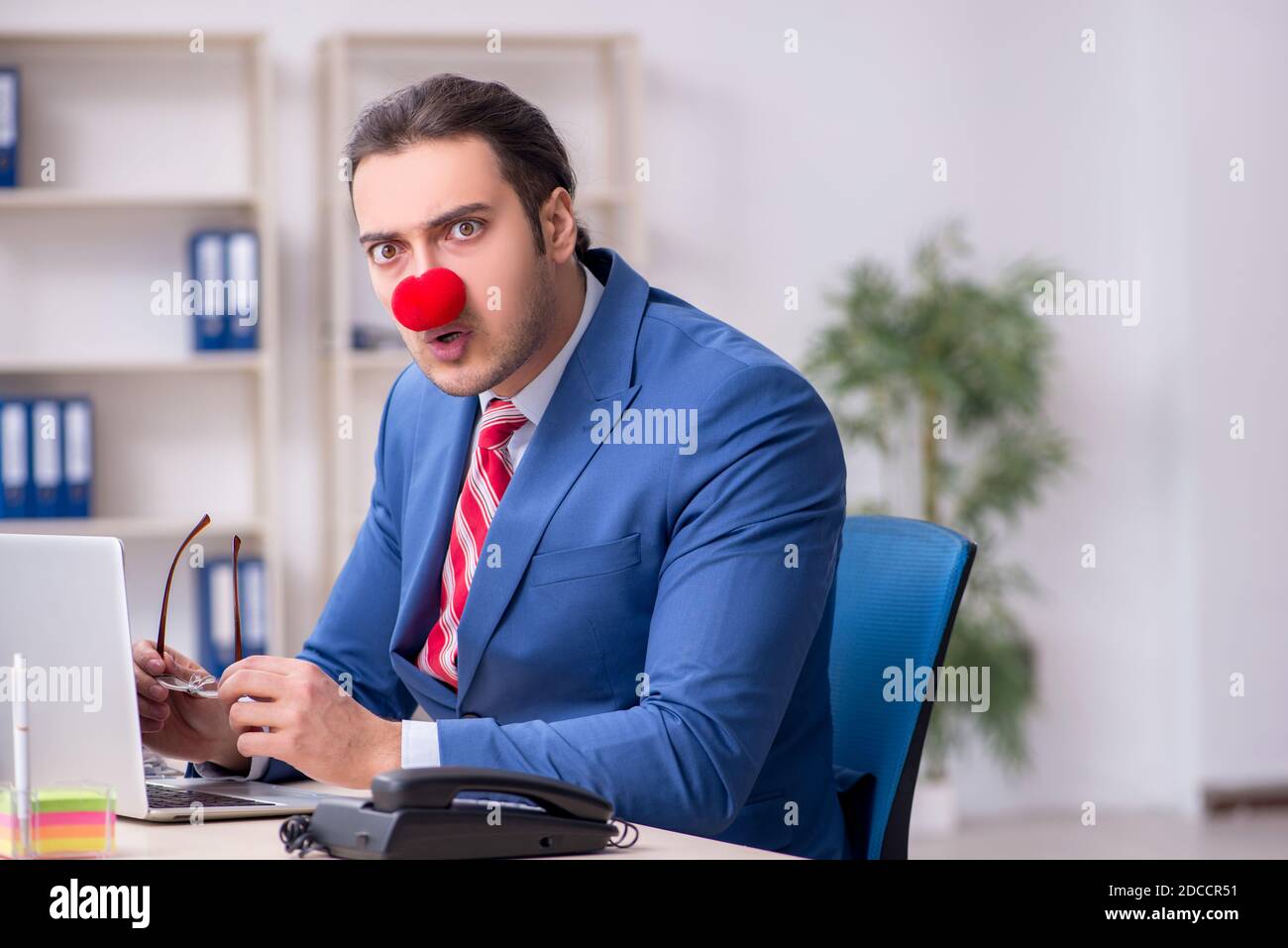 Funny employee clown working in the office room Stock Photo - Alamy