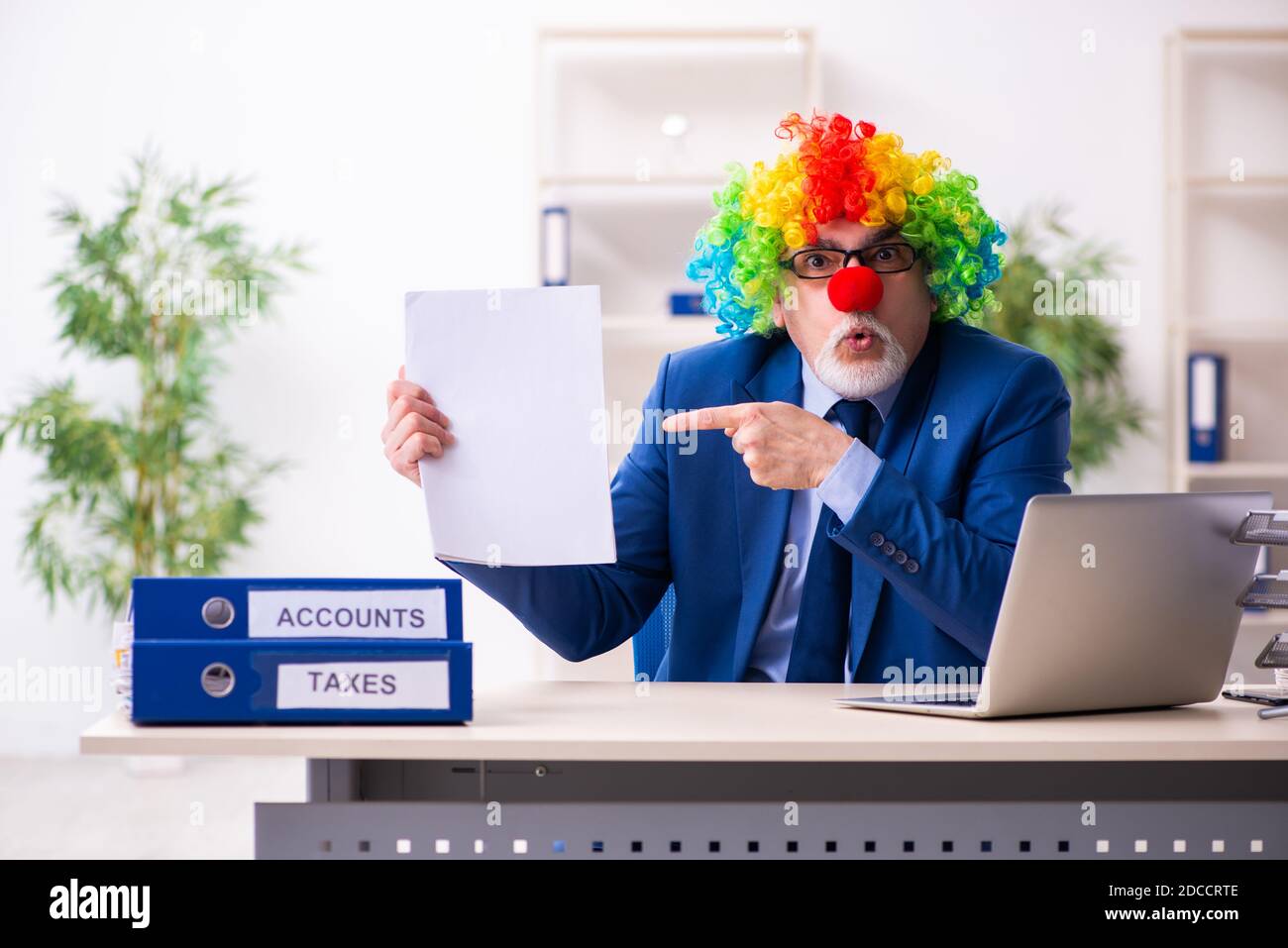 Aged businessman clown working in the office Stock Photo - Alamy