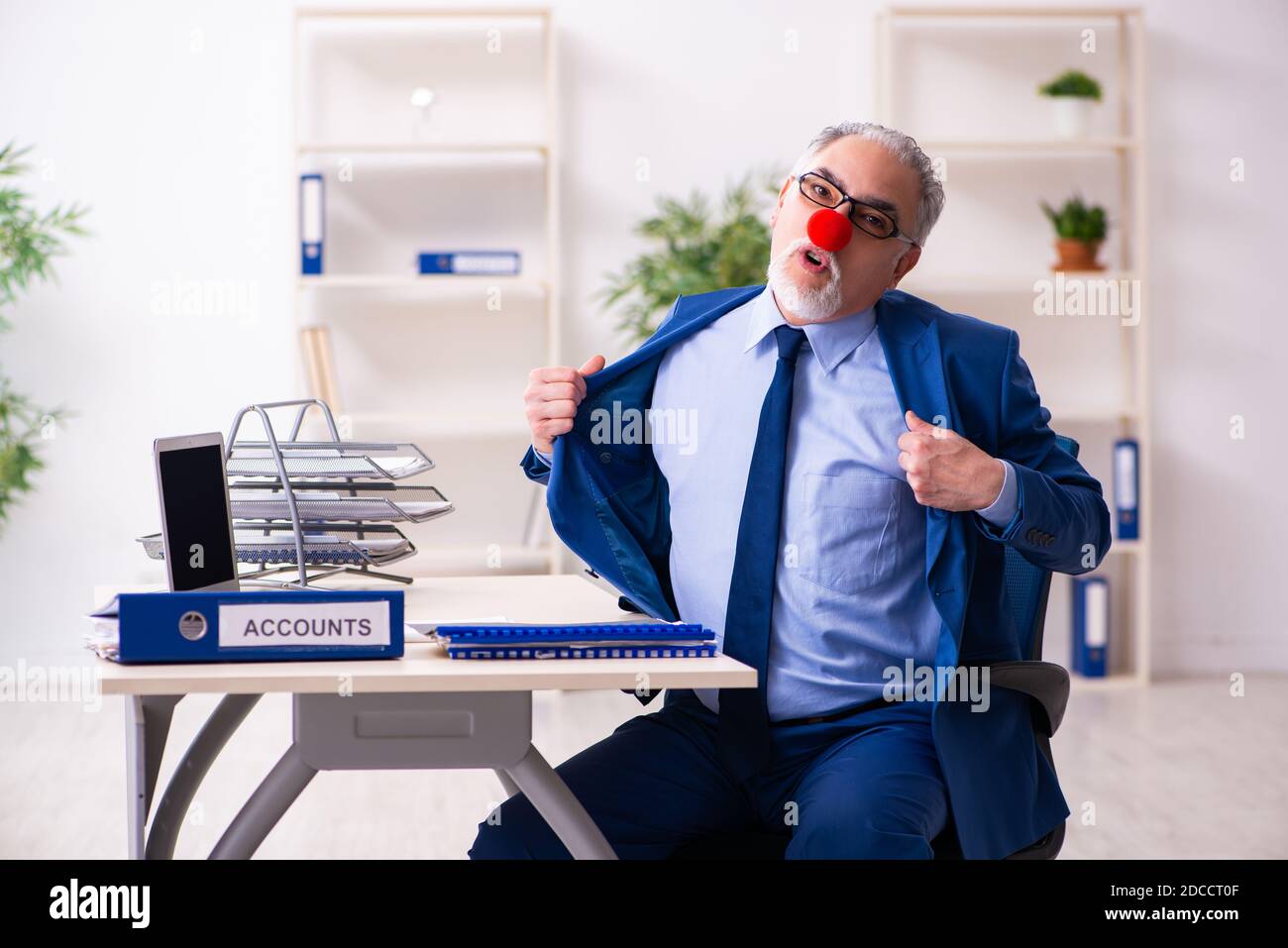 Aged businessman clown working in the office Stock Photo - Alamy