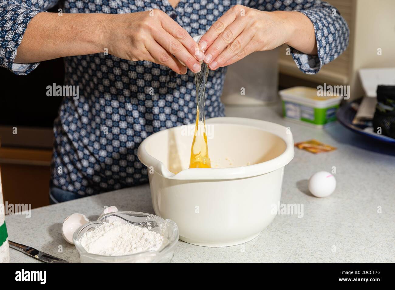 A home baker breaking an egg over a white bowl on a kitchen counter Stock Photo - Alamy