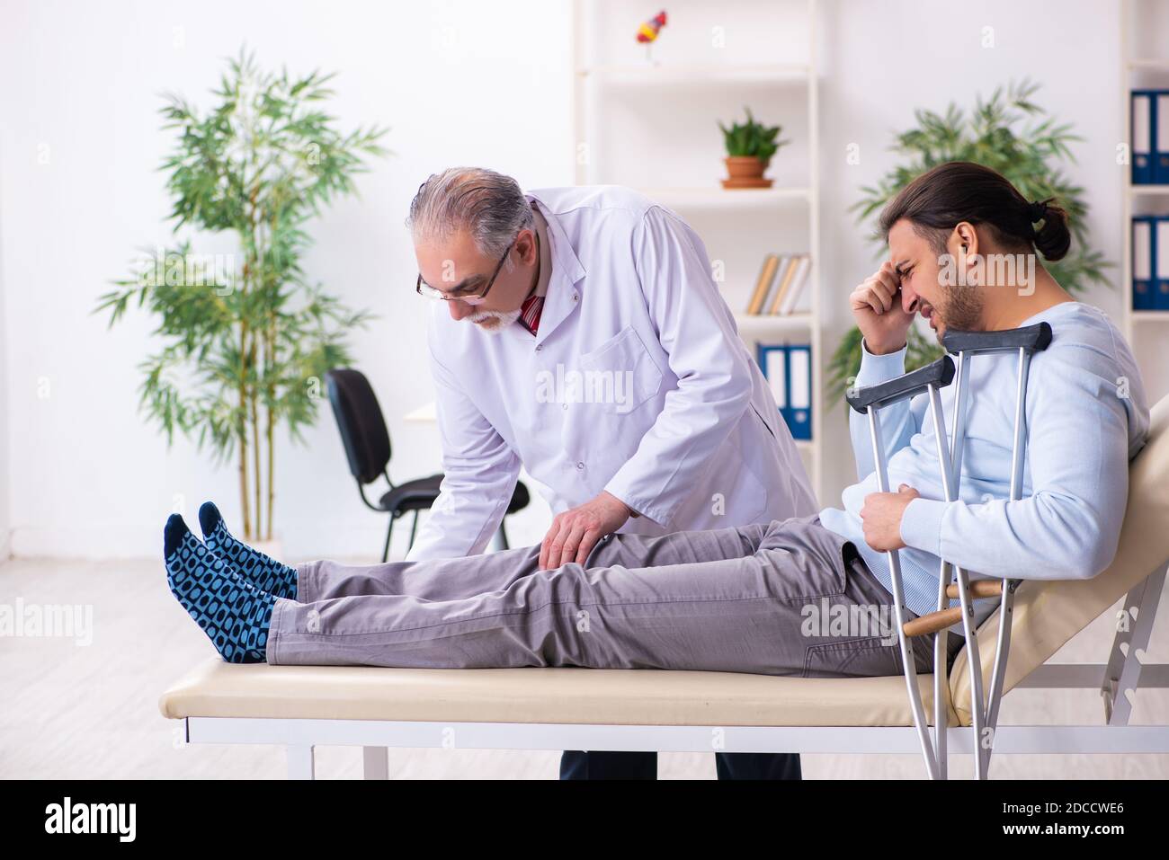 Leg injured man visiting old doctor osteopath Stock Photo - Alamy