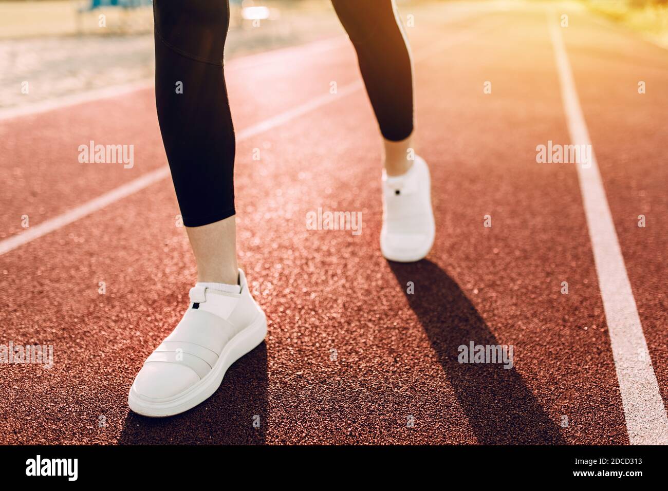 Close-up of women's feet in athletic shoes running around the stadium ...