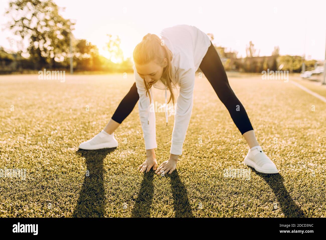 Slender girl athlete in sports clothes, doing stretching in the morning ...