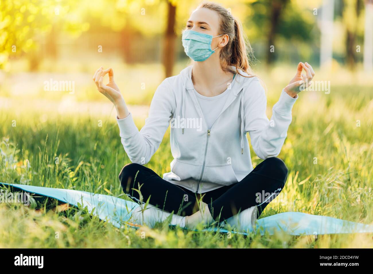 girl in a medical protective mask meditates in the Lotus position on ...