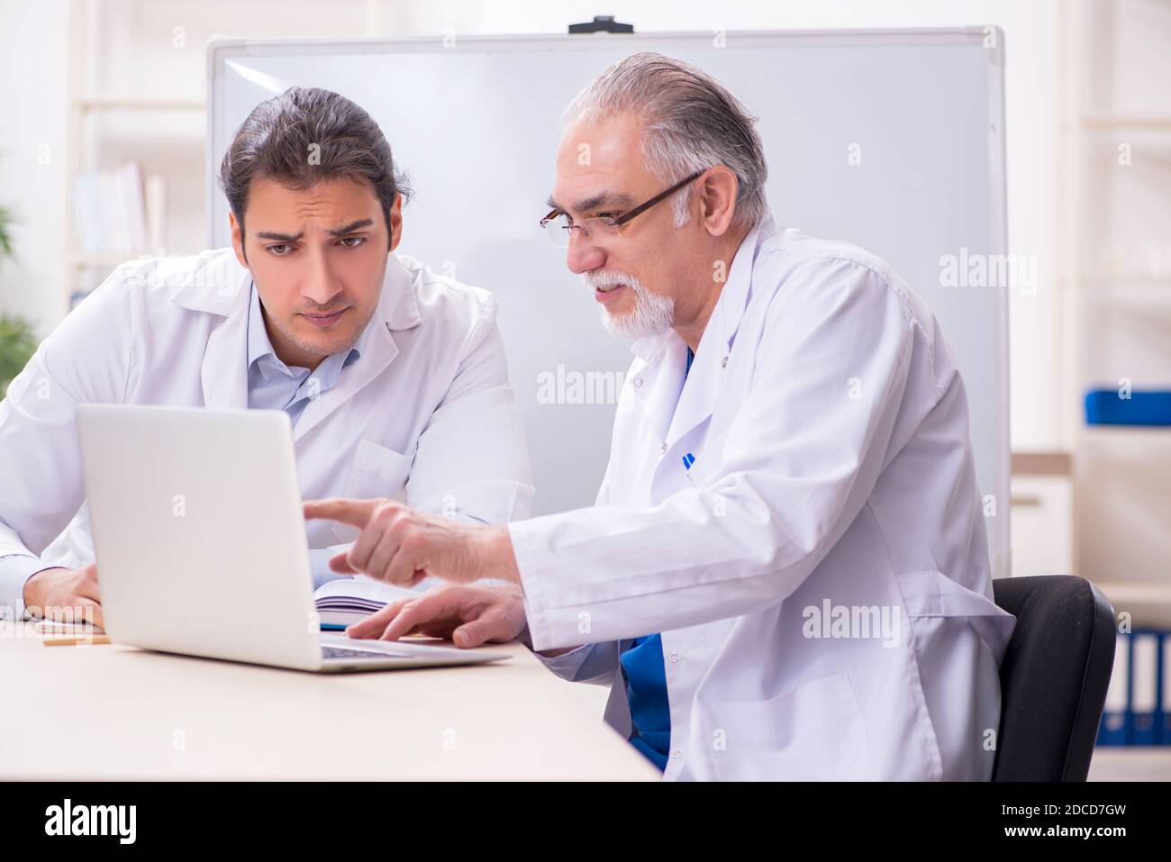 Experienced doctor teaching young assistant using computer Stock Photo ...