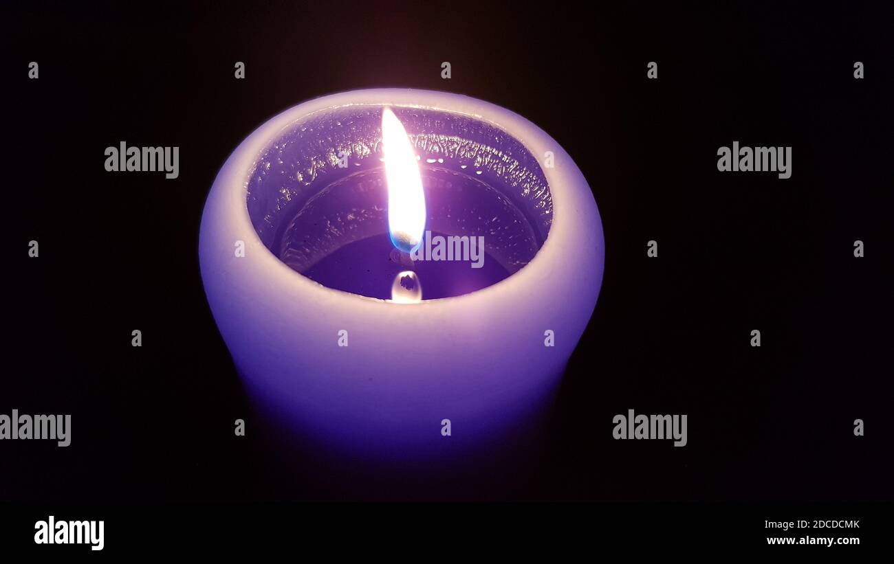 Candlelight flame closeup on black background. Burning fire of purple ...