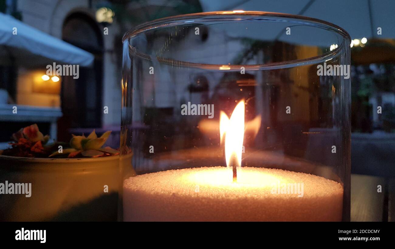 Transparent glass candle holder with flame inside. Burning fire of ...