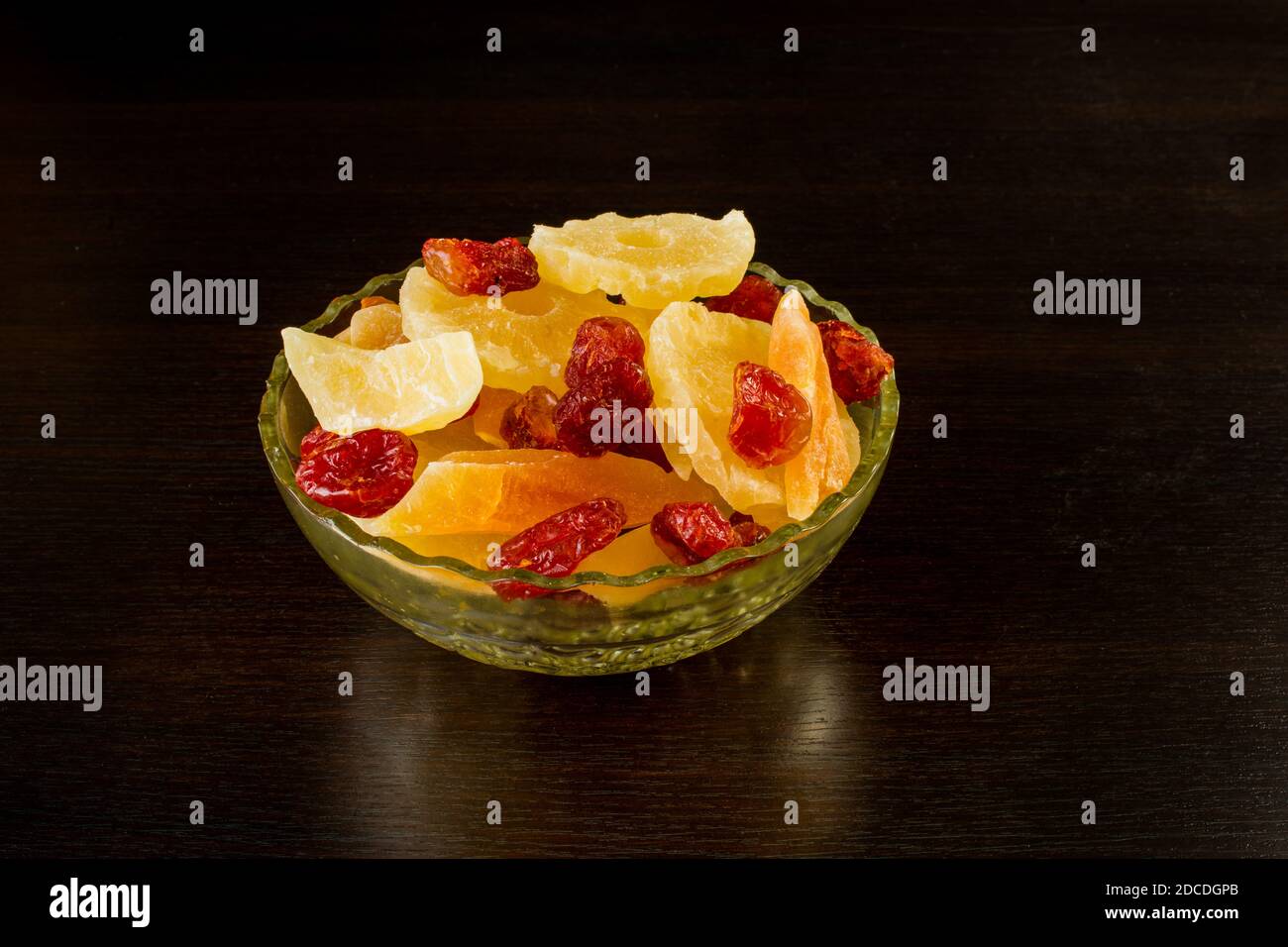 Yellow candied melon slices, pineapple rings and dogwood in a glass ...