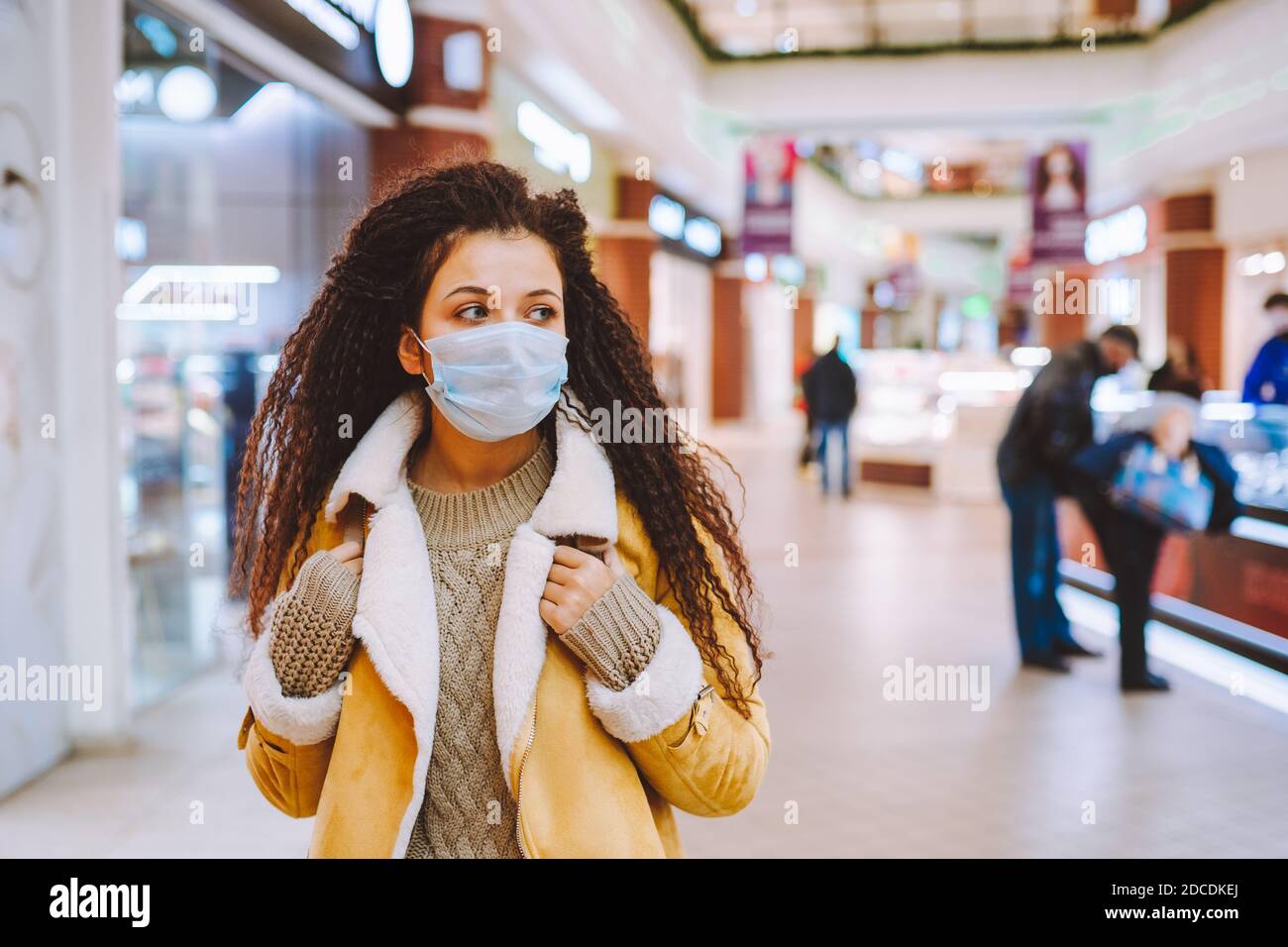 Beautiful afro haired woman wearing protective medical face mask in ...