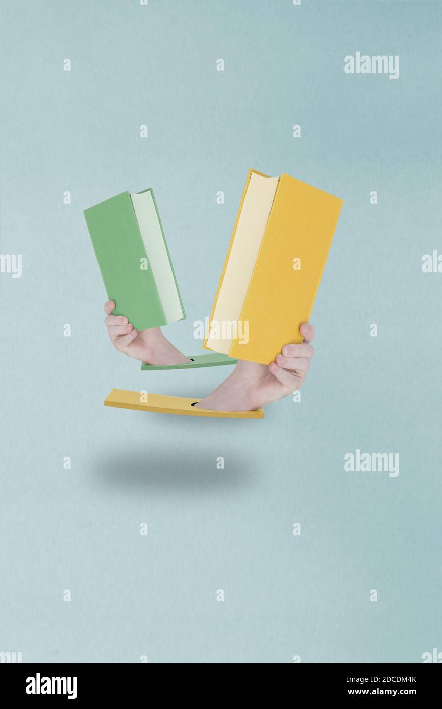 Two books held by hands float in the air close to each other as if ...