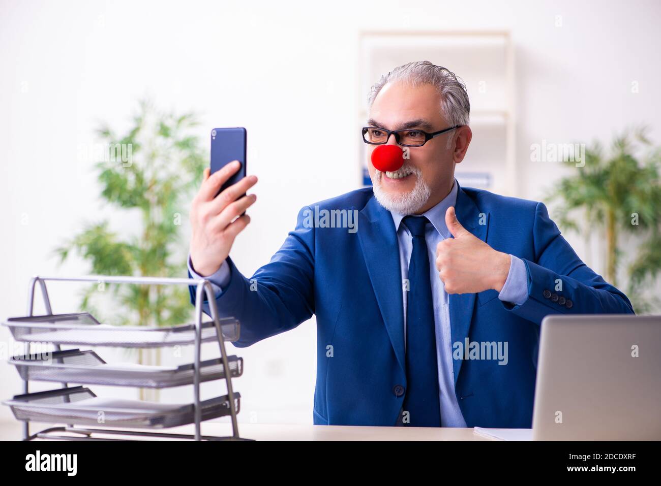 Aged businessman clown working in the office Stock Photo - Alamy