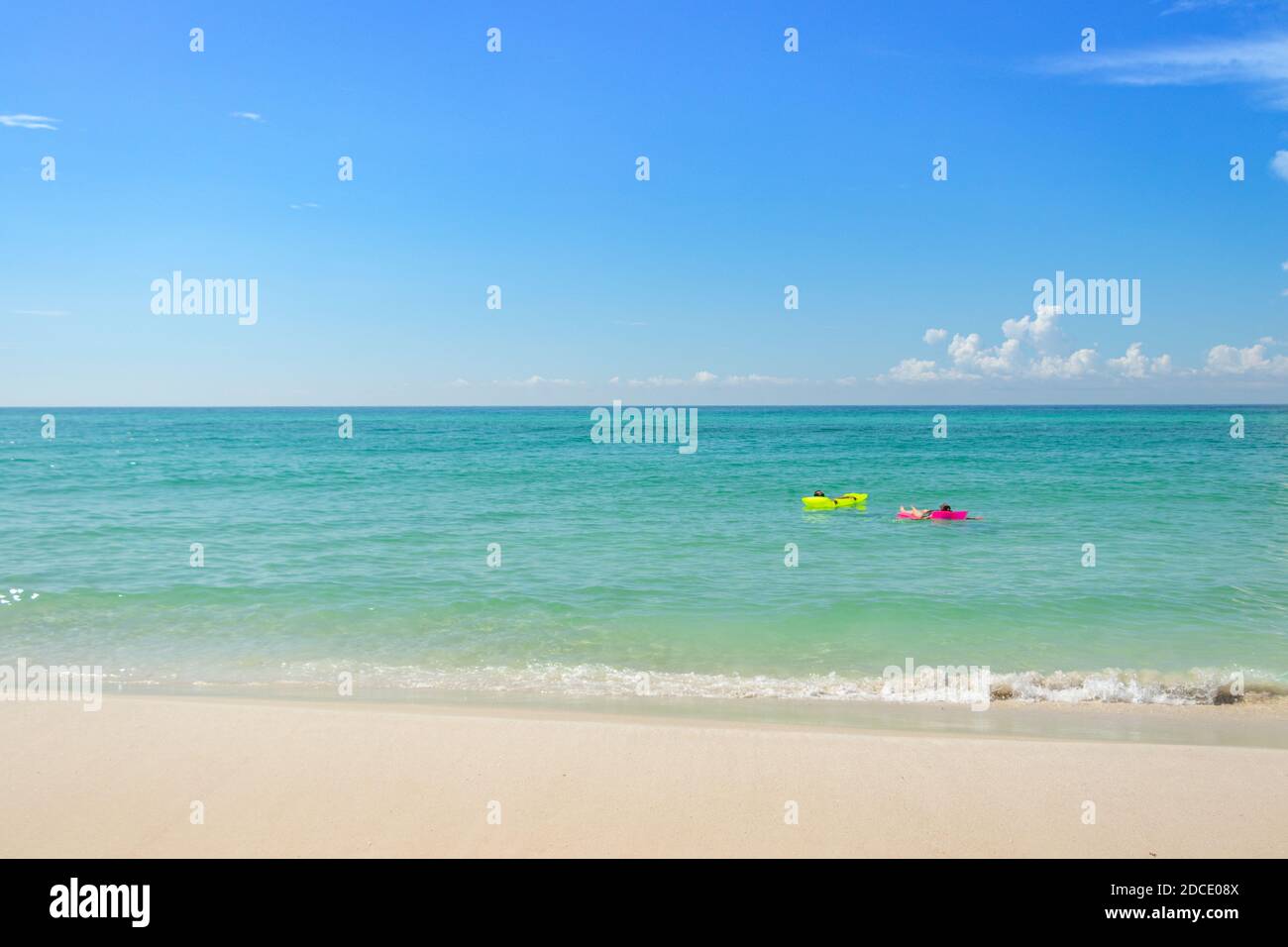 couple swimming in green sea with fluorescent lilo inflatable at beach ...