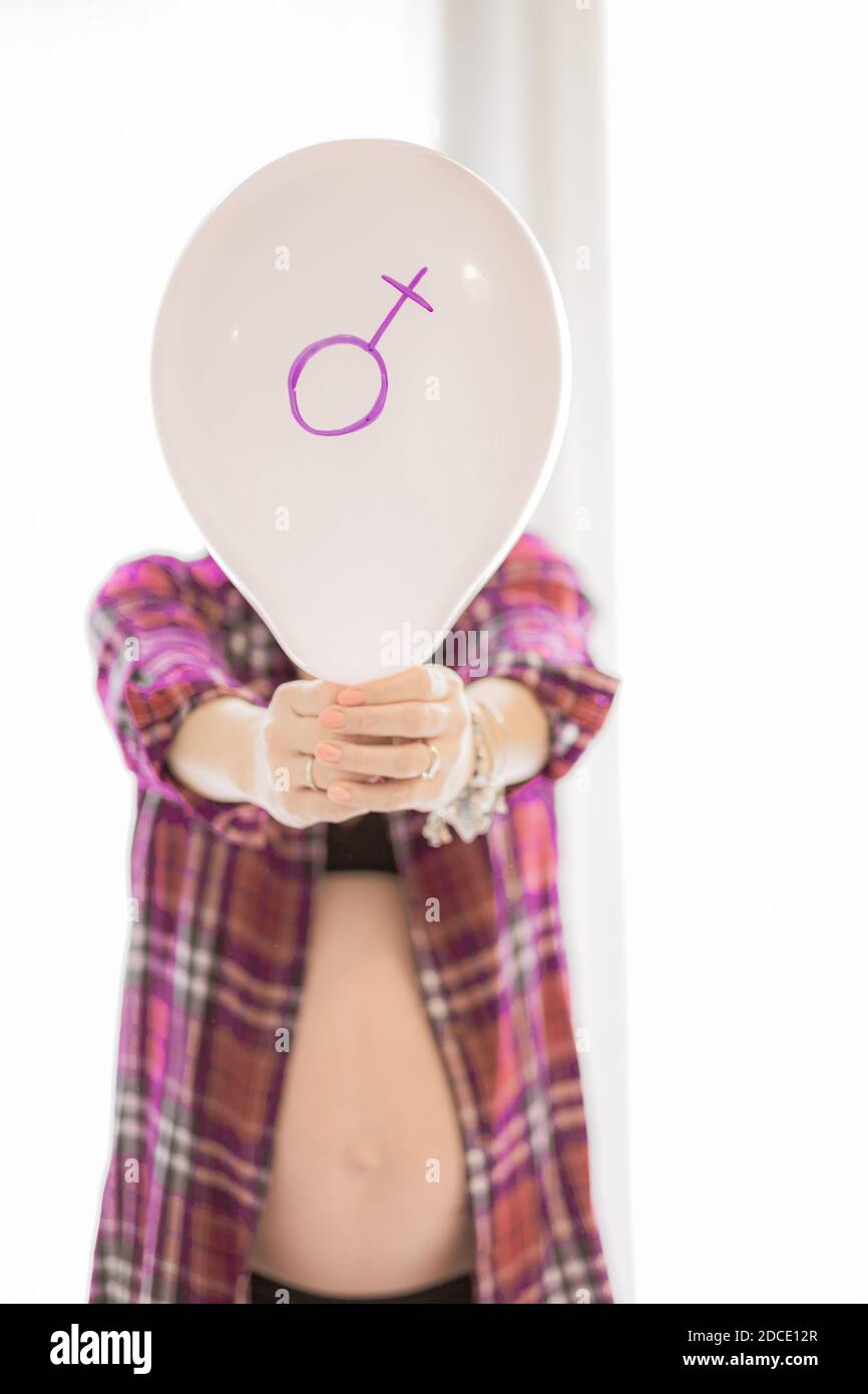 A pregnant woman is holding a pink balloon - Young pregnant girl is ...