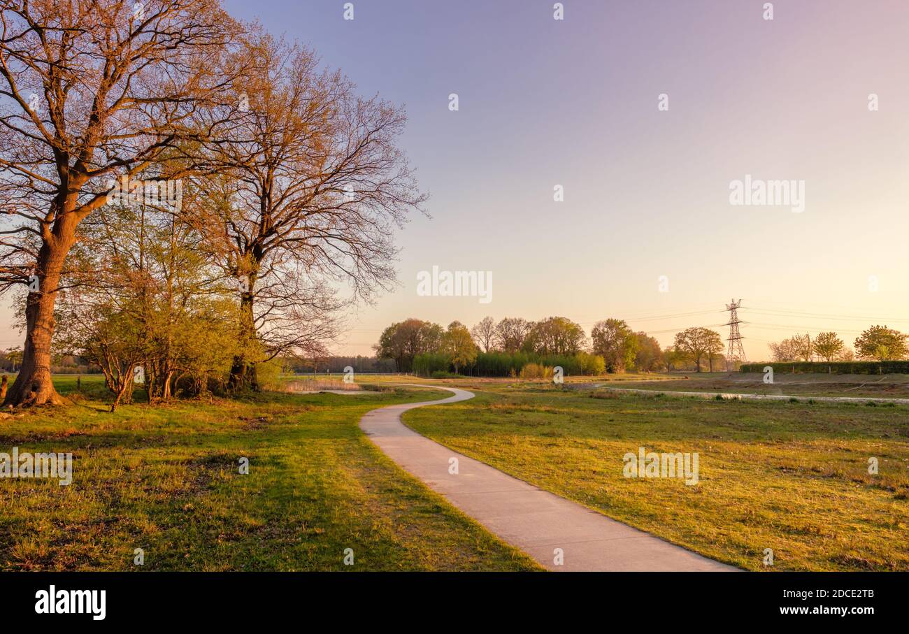 Sweeping bicycle trail in a Dutch farm landscape during sunset. It is ...