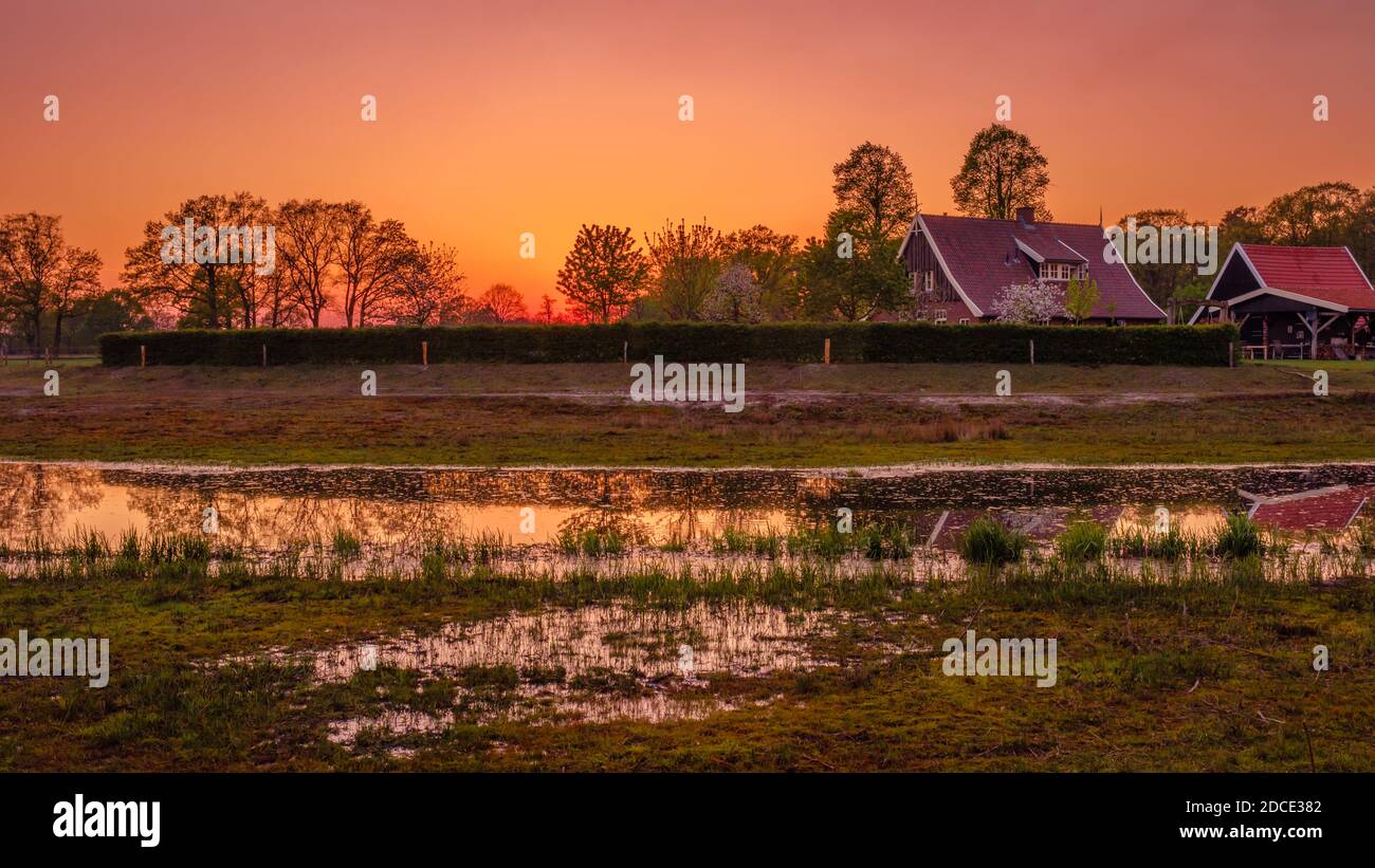 Traditional farm located along a river and ponds. The sun is setting in ...