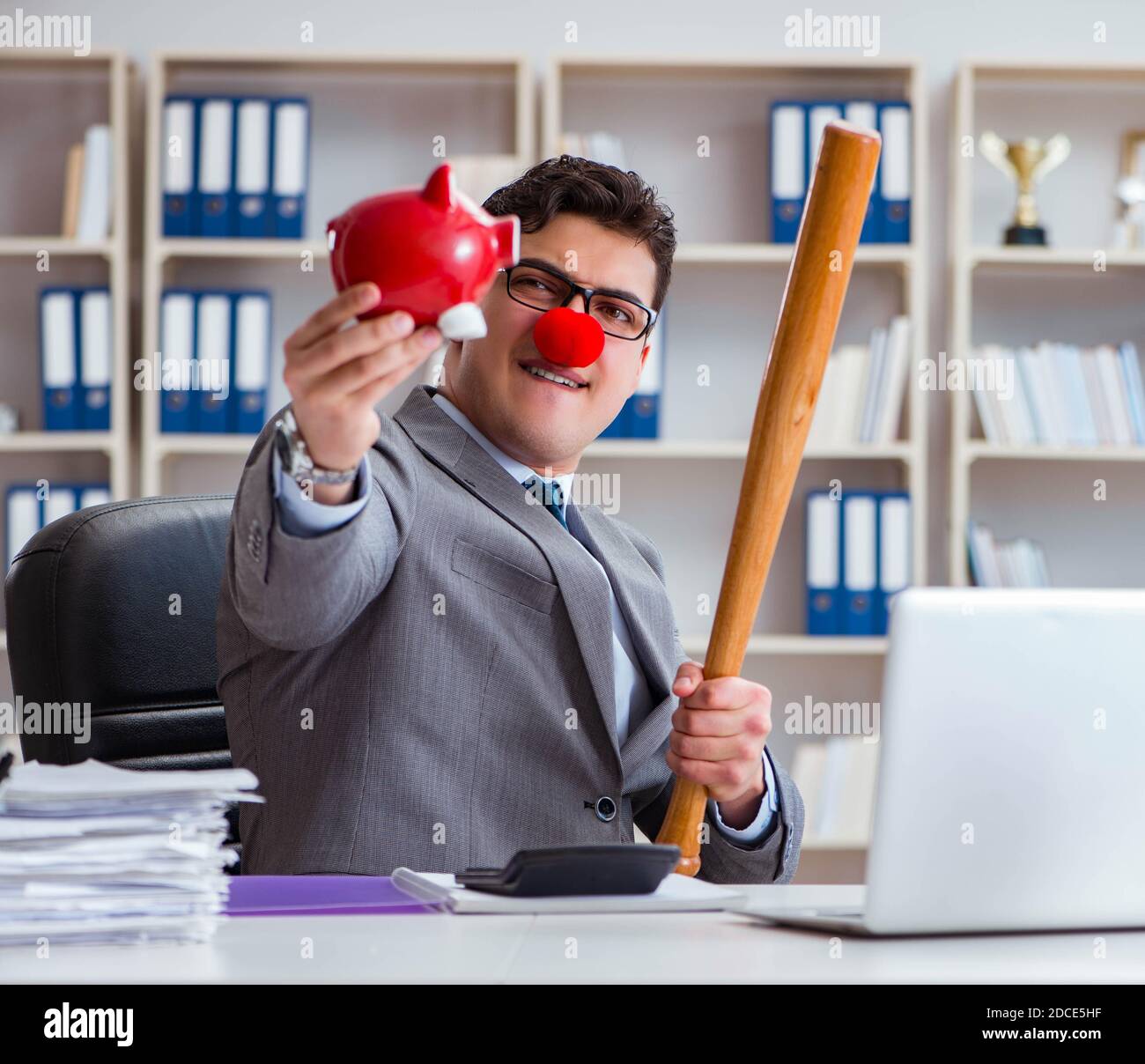 The clown businessman with a baseball bat and a piggy bank Stock Photo ...