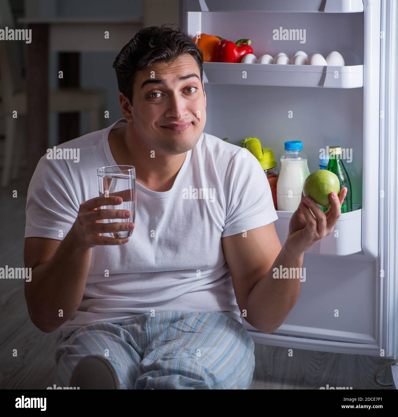 The man at the fridge eating at night Stock Photo - Alamy