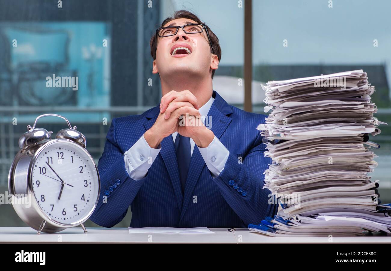 Businessman with pile stack of paper paperwork and an alarm clock ...